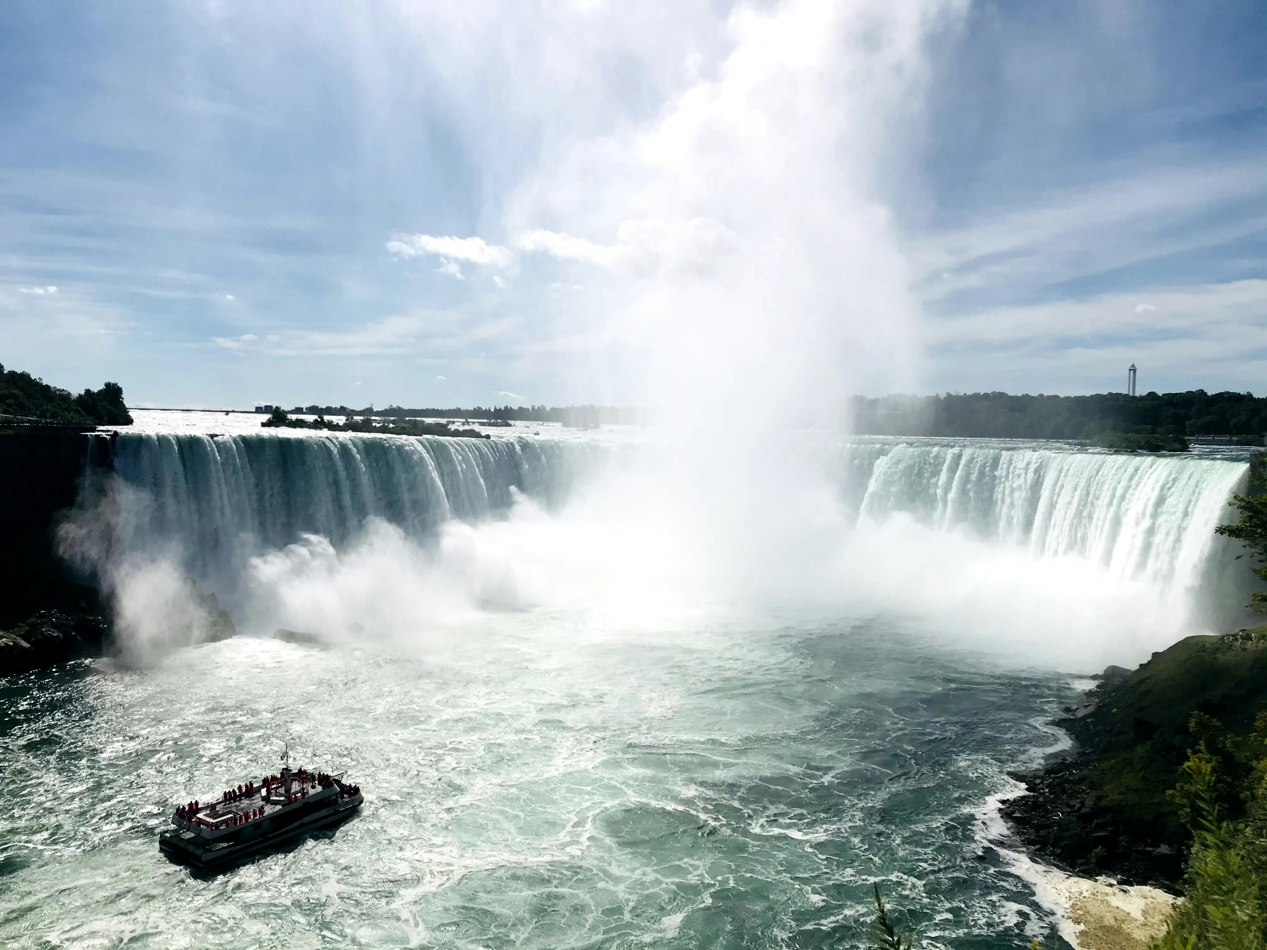 Powerful waterfall plunging into a vast basin with mist rising under a clear sky.