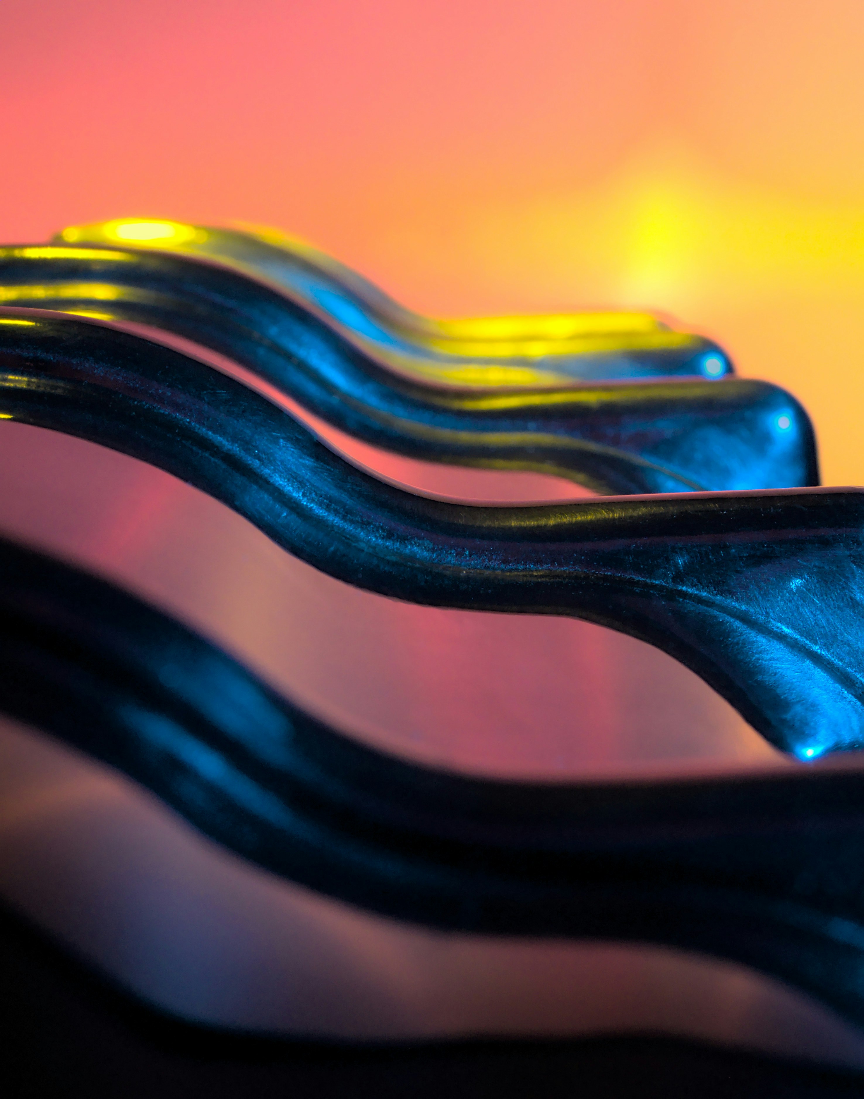 Curved handles of a griddle reflecting vibrant colored lights against a warm background.