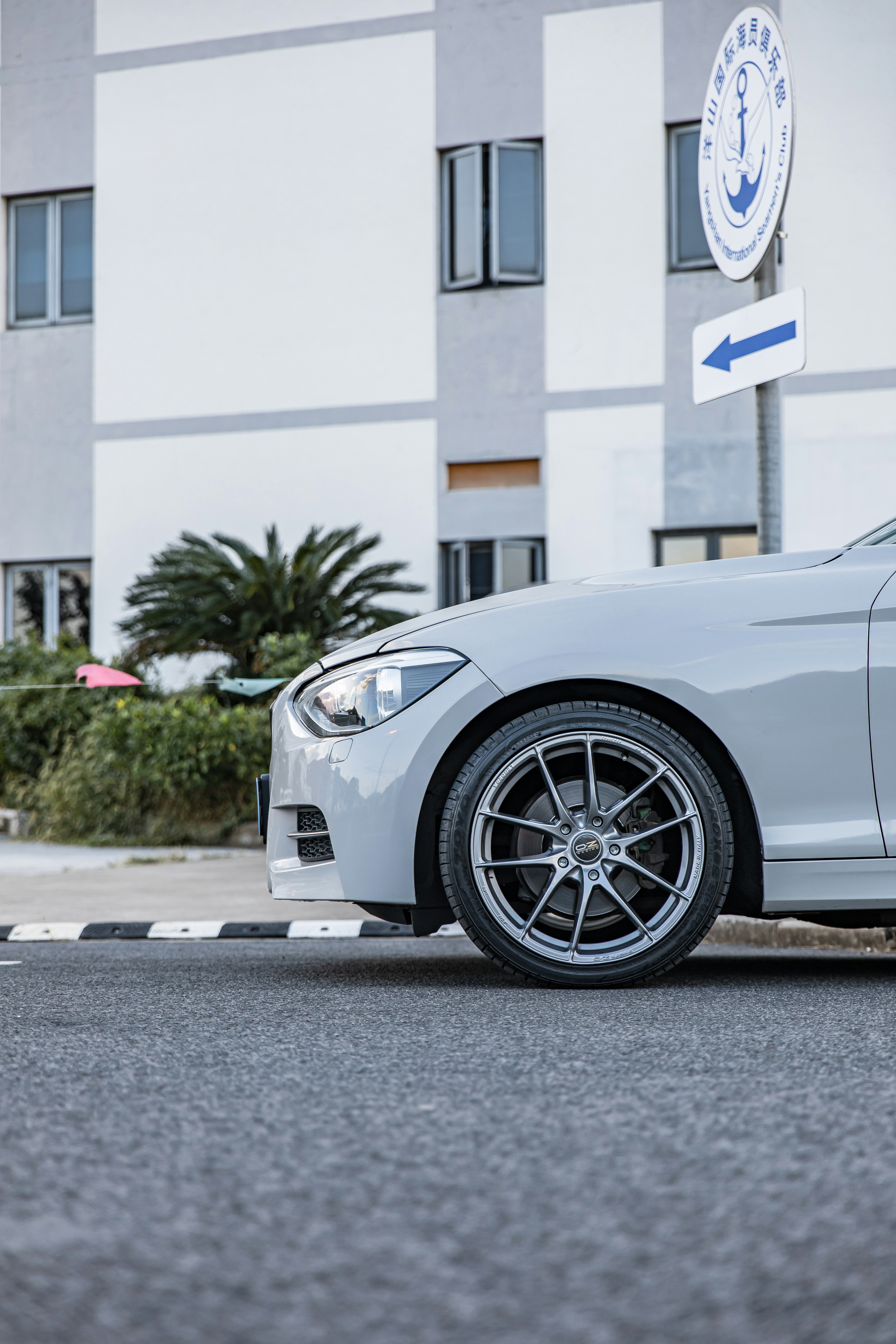 Edge of Precision: Silver Sport Wheel Beside a Modern Facade