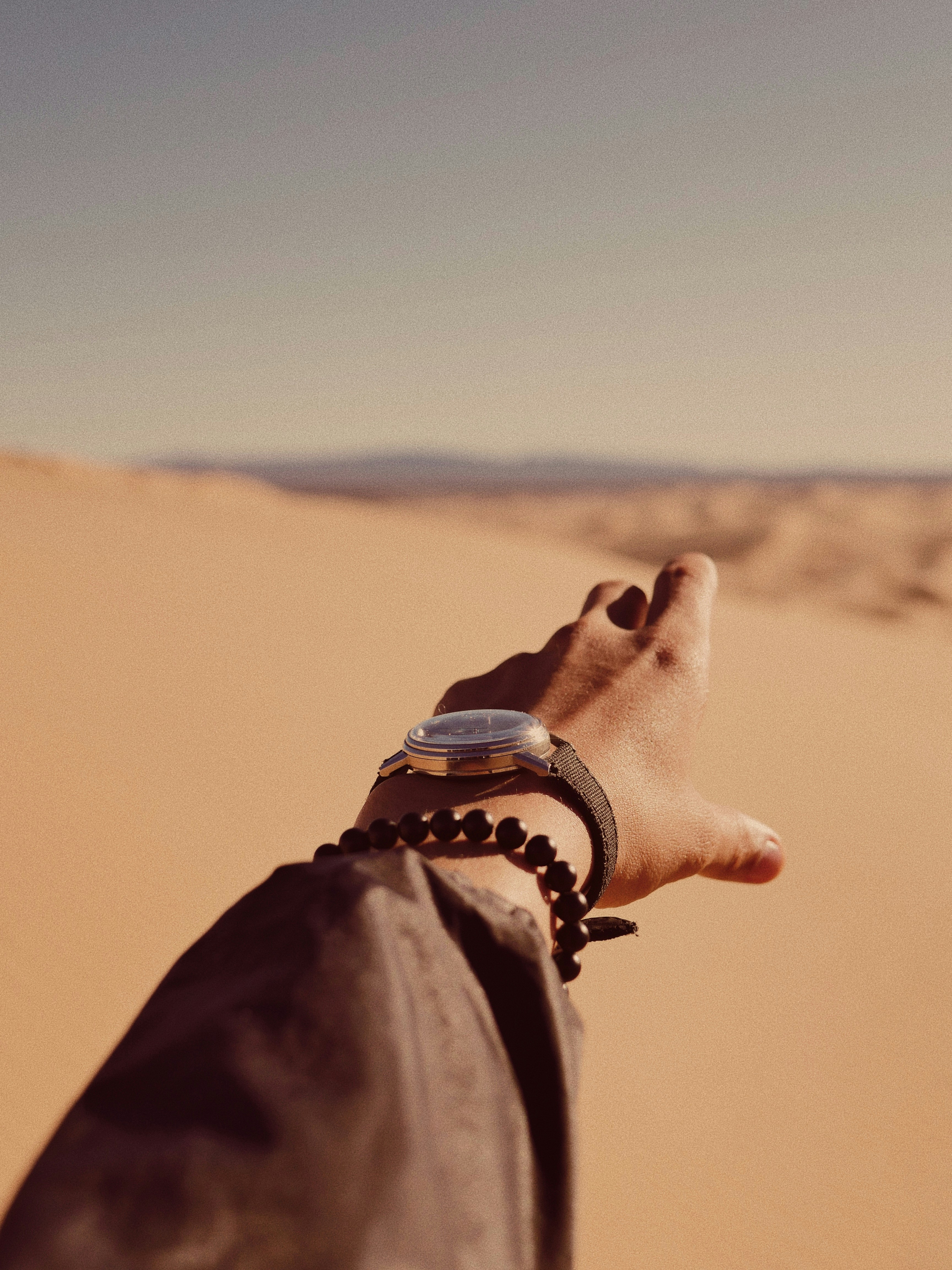 Timekeeper at the Dunes: A Hand Extends Toward the Horizon