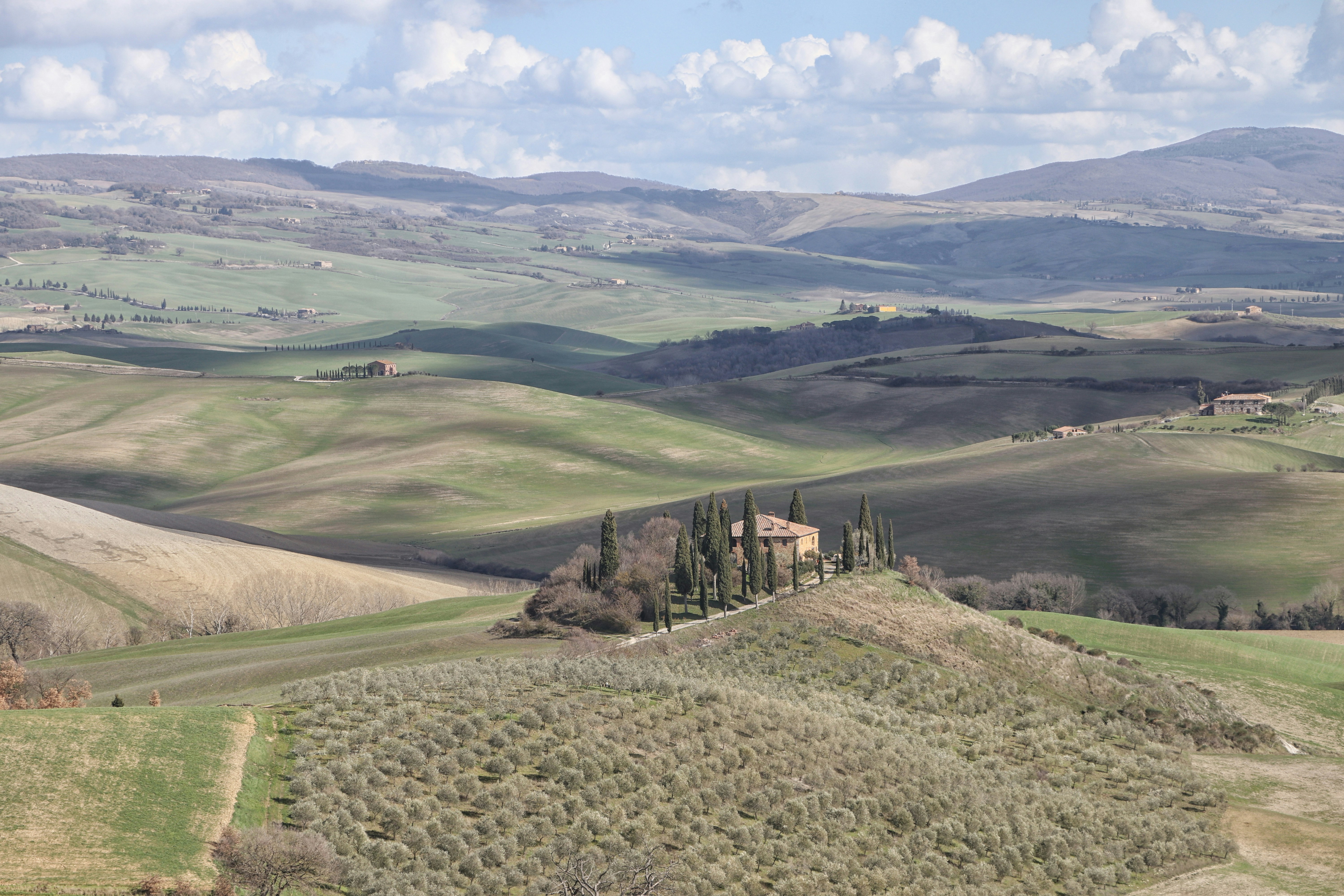 Tuscan farmhouse nestled among green hills under a vibrant sky.