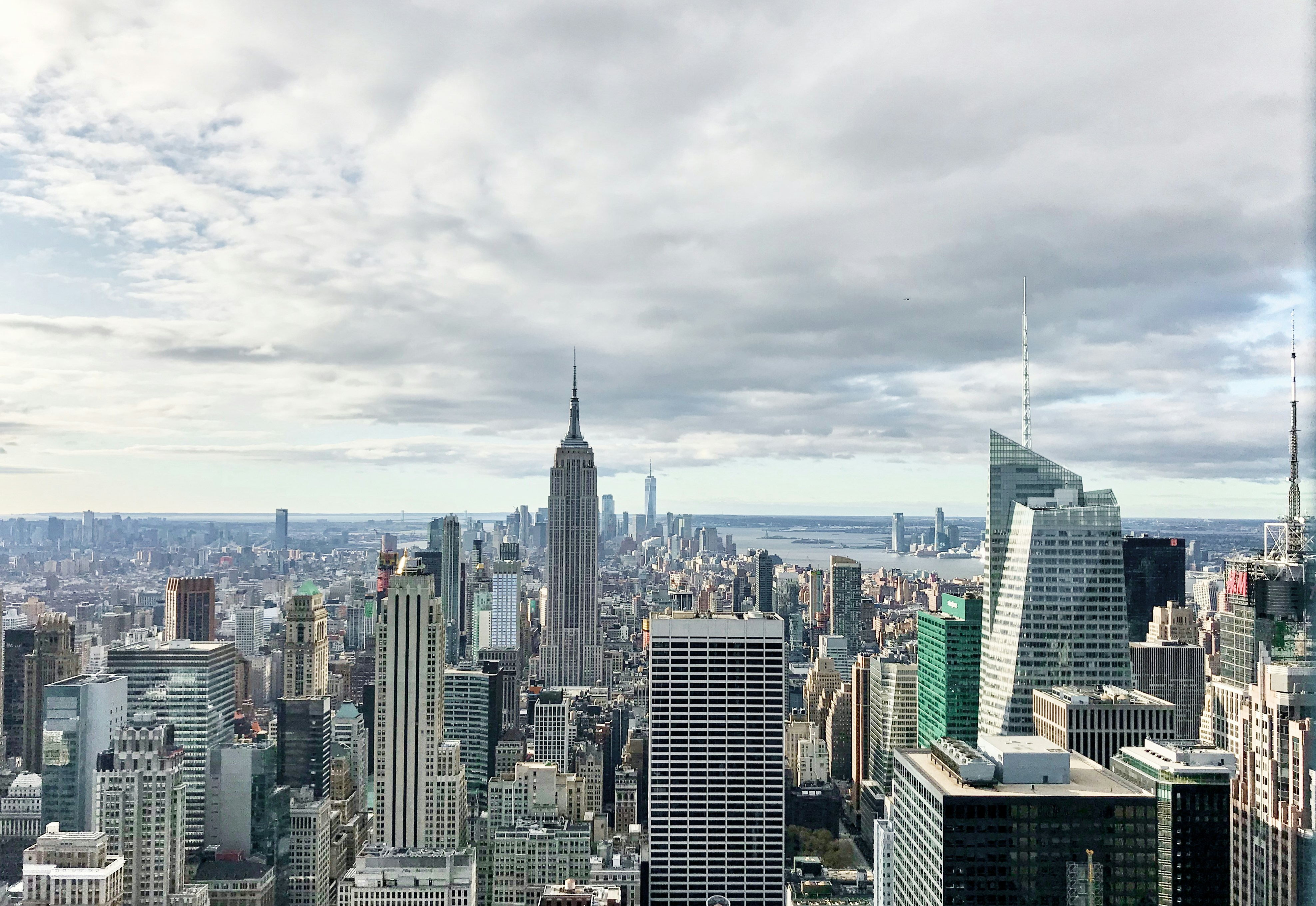 A panoramic view of Manhattan showcasing the Empire State Building amidst a sea of skyscrapers under a dynamic sky.