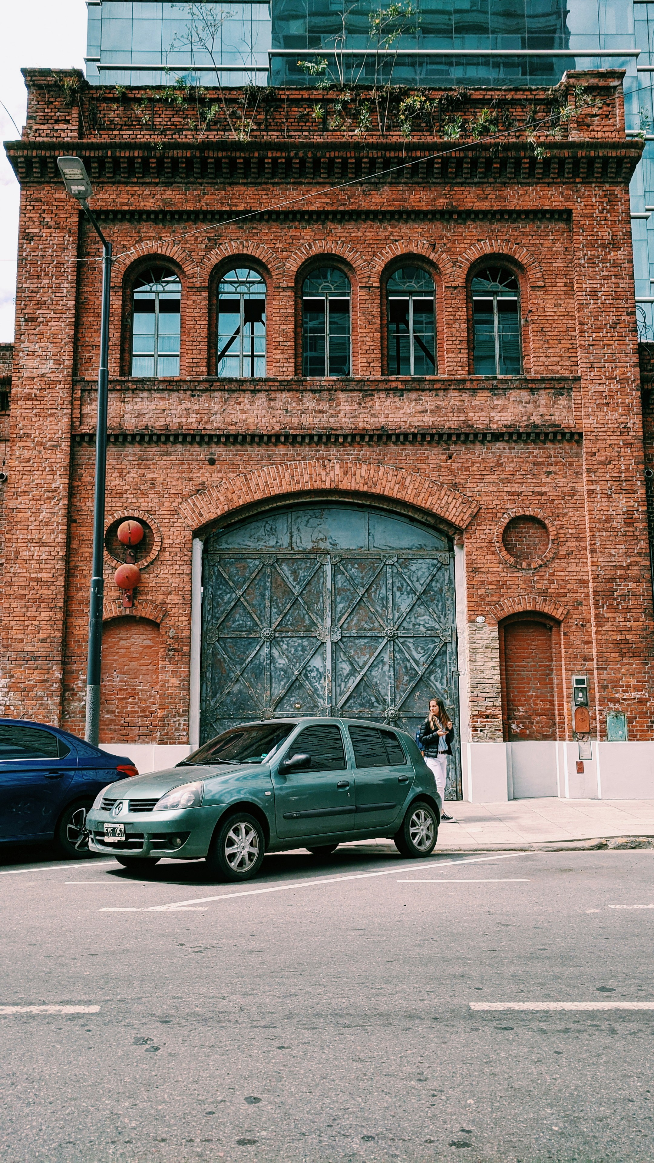Green hatchback against a brick facade: a quiet city street scene