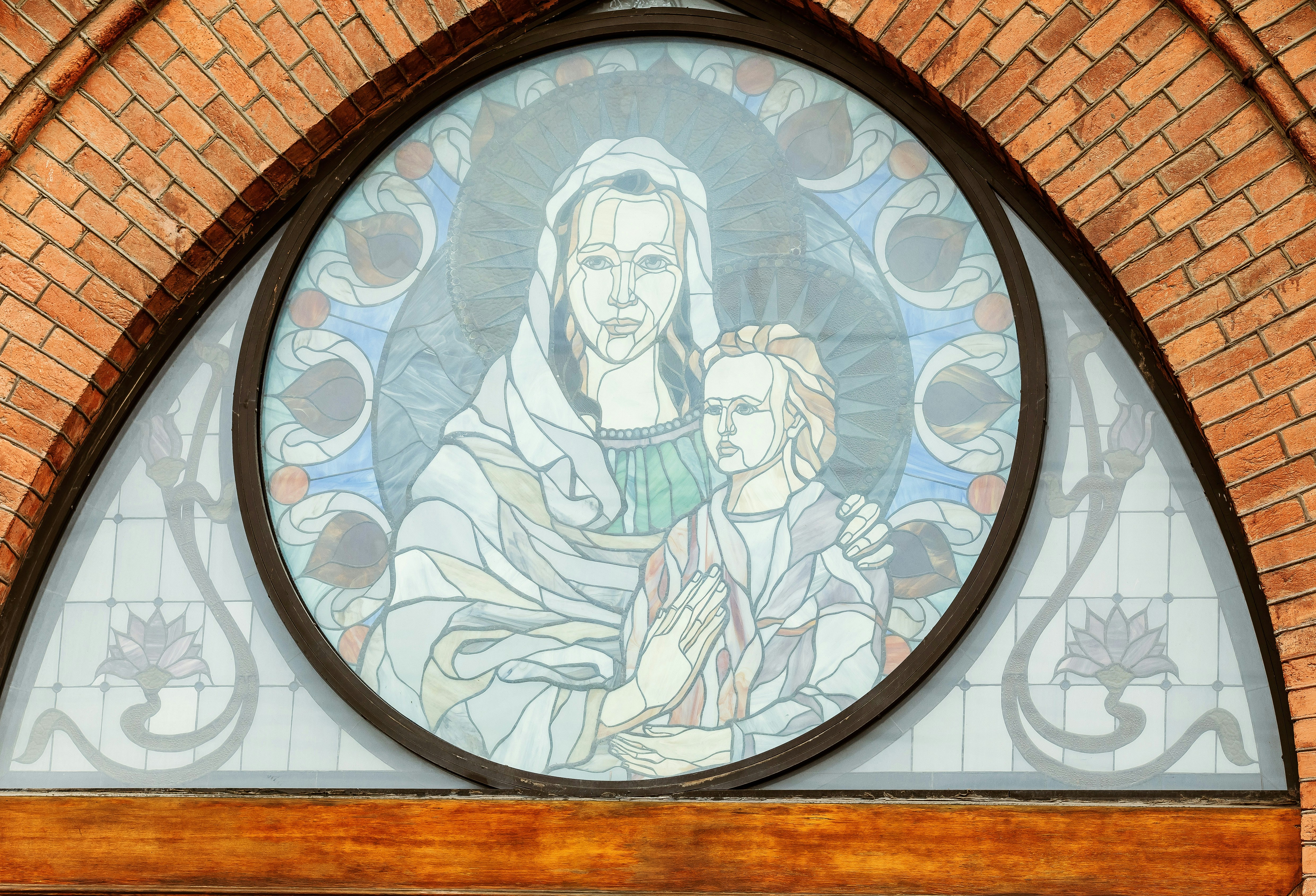 Stained-glass window depicting saints at the entrance of a Catholic church with intricate details.