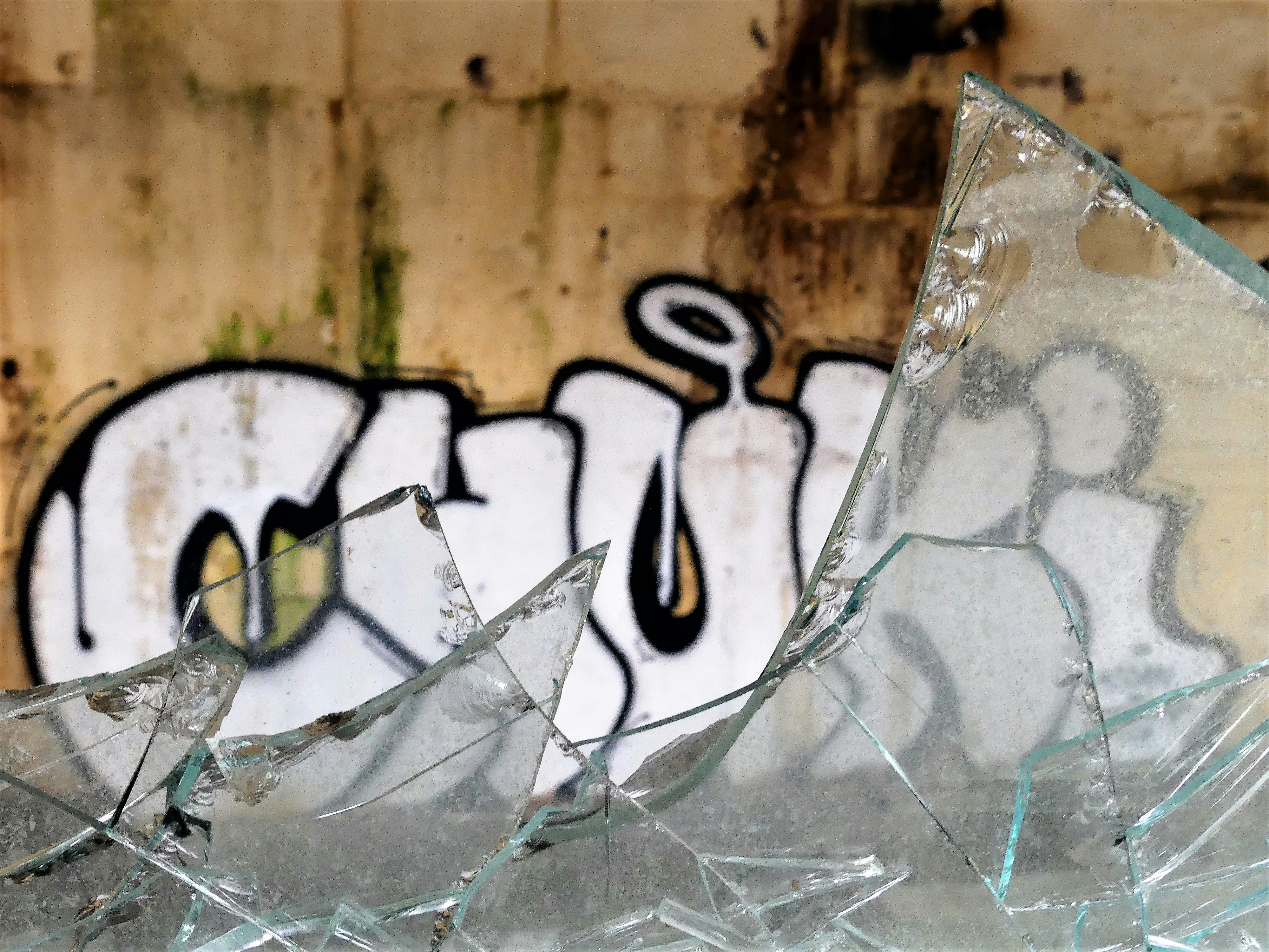 Shattered Glass Fragments Framing Graffiti on a Weathered Wall
