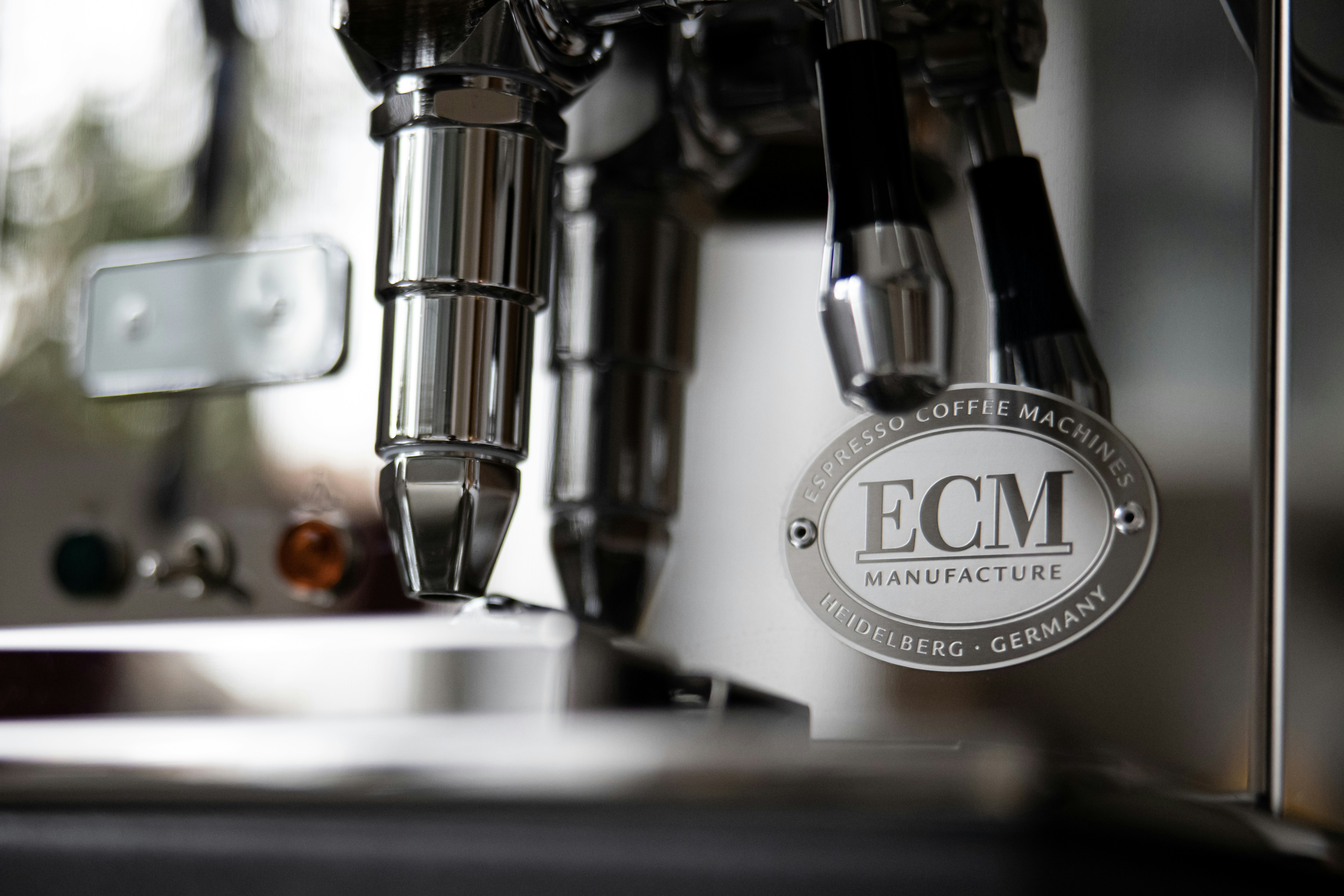 Stainless Precision: Close-Up of ECM Espresso Machine’s Portafilter and Branding Badge