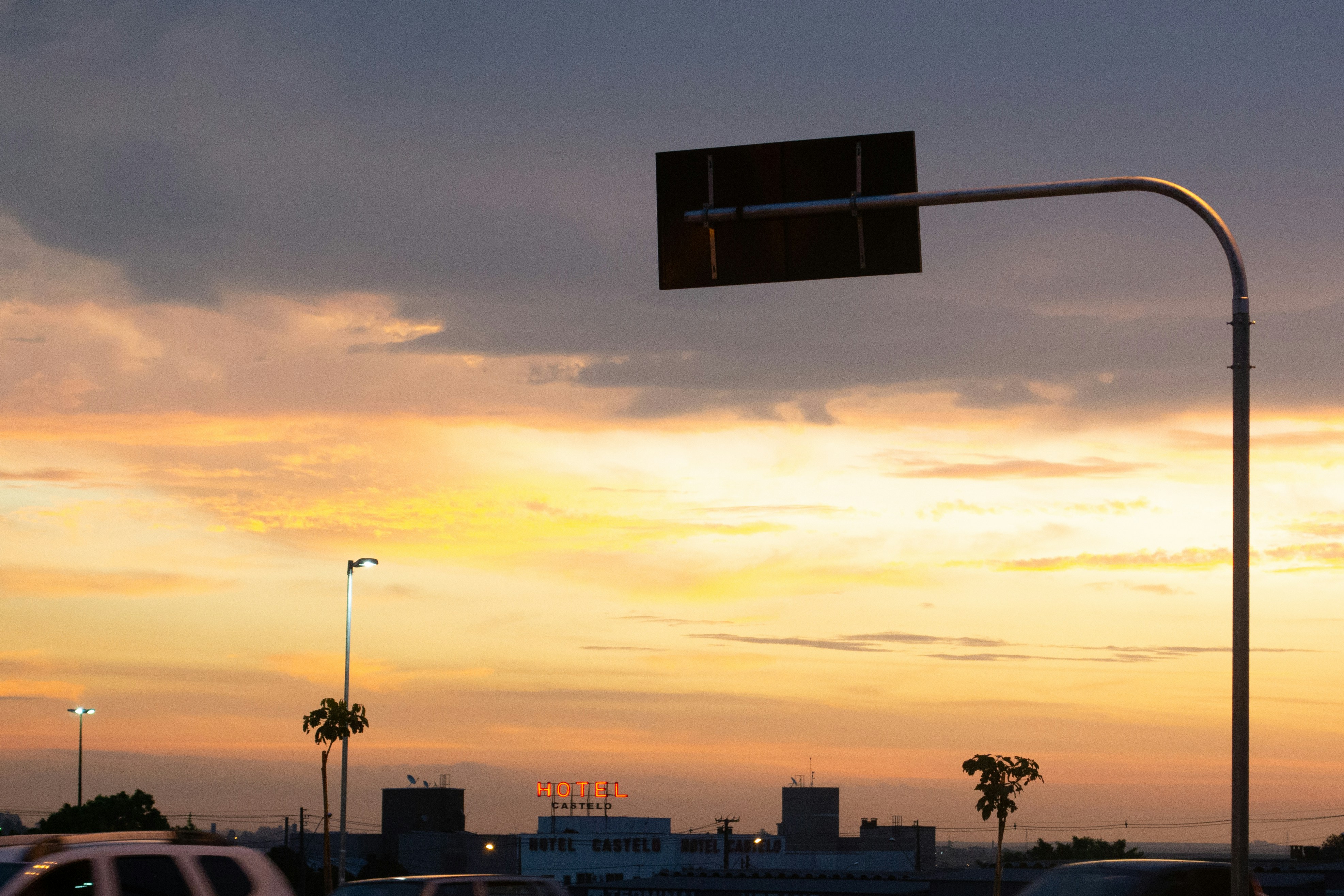 Silhouette of streetlights and distant buildings against a vibrant sunset sky.