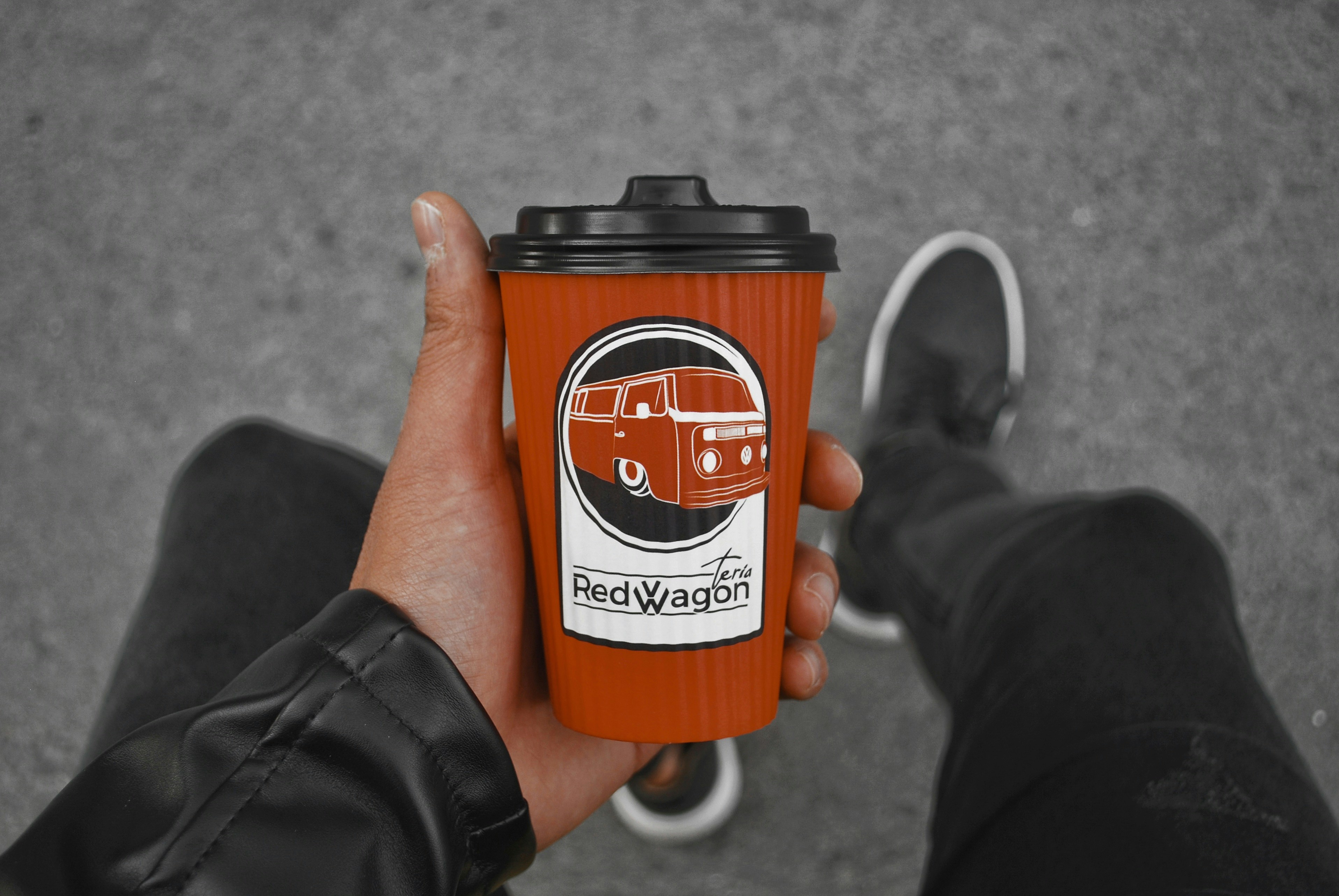 Orange Cup on a Monochrome Street: A Handheld Moment with Red Wagon