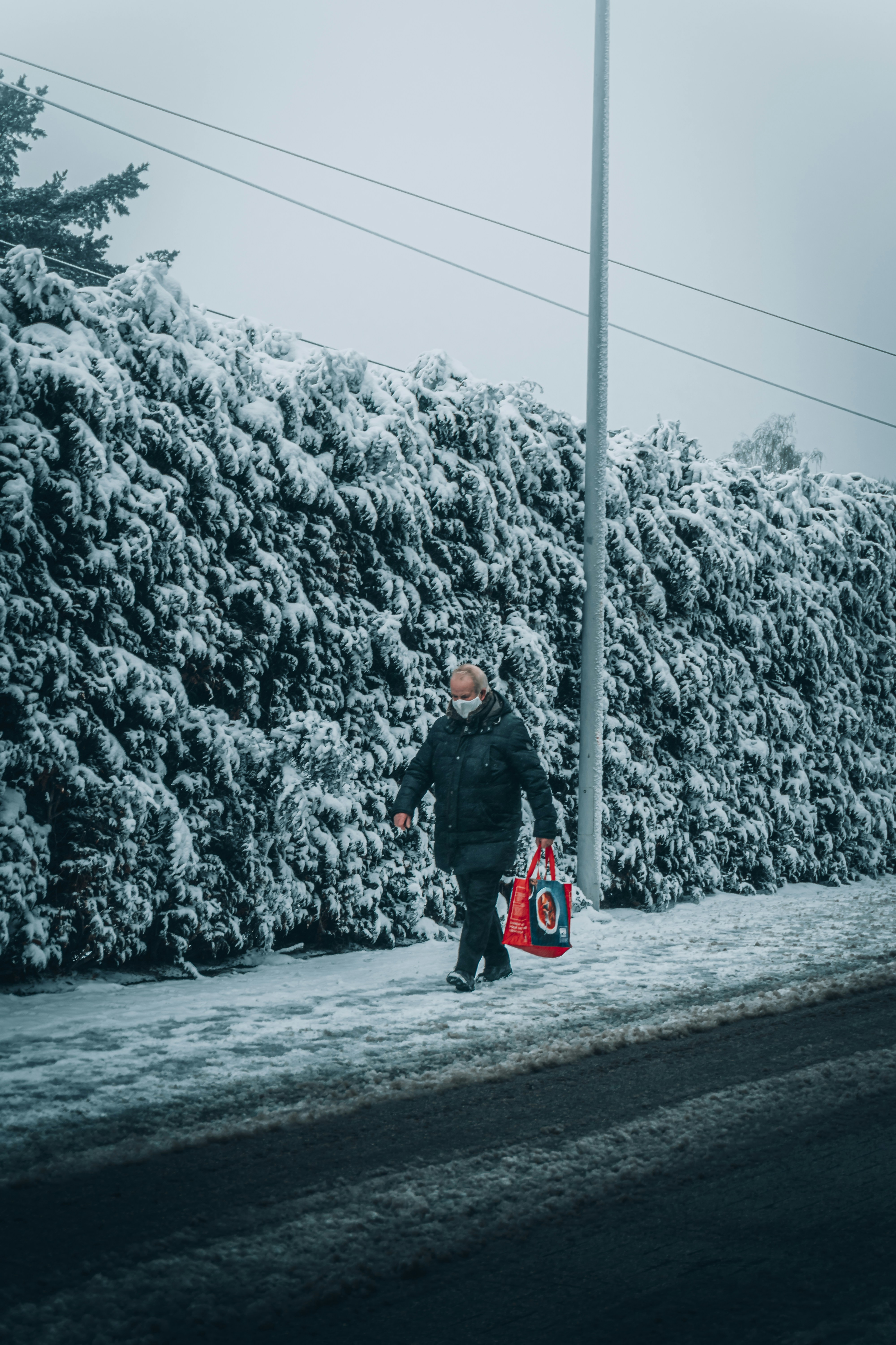 Snowbound Crossing: A lone pedestrian with a red bag on a quiet winter street