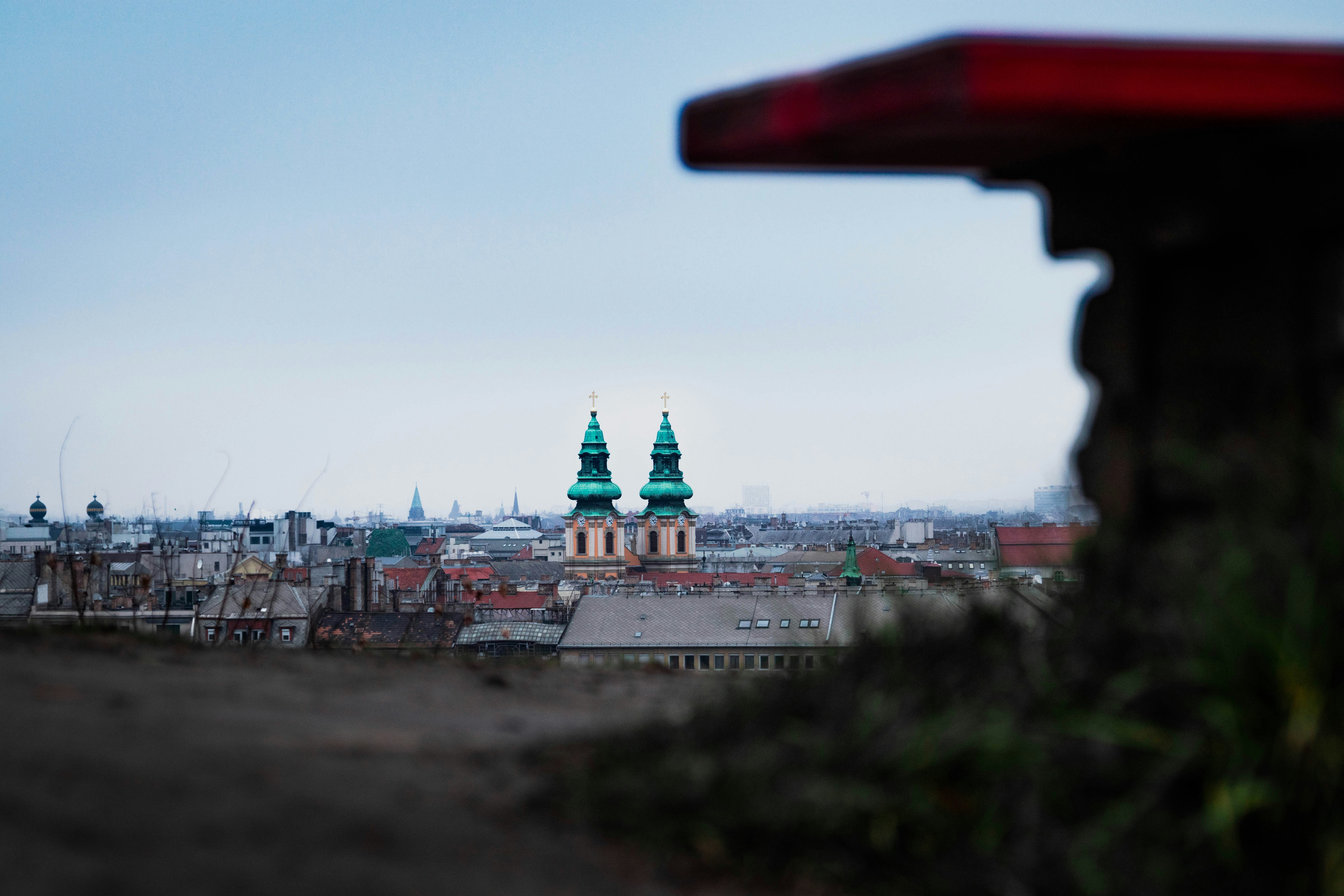 Historic twin spires rise above the urban landscape, framed by a blurred foreground. The scene captures a tranquil moment in the city.