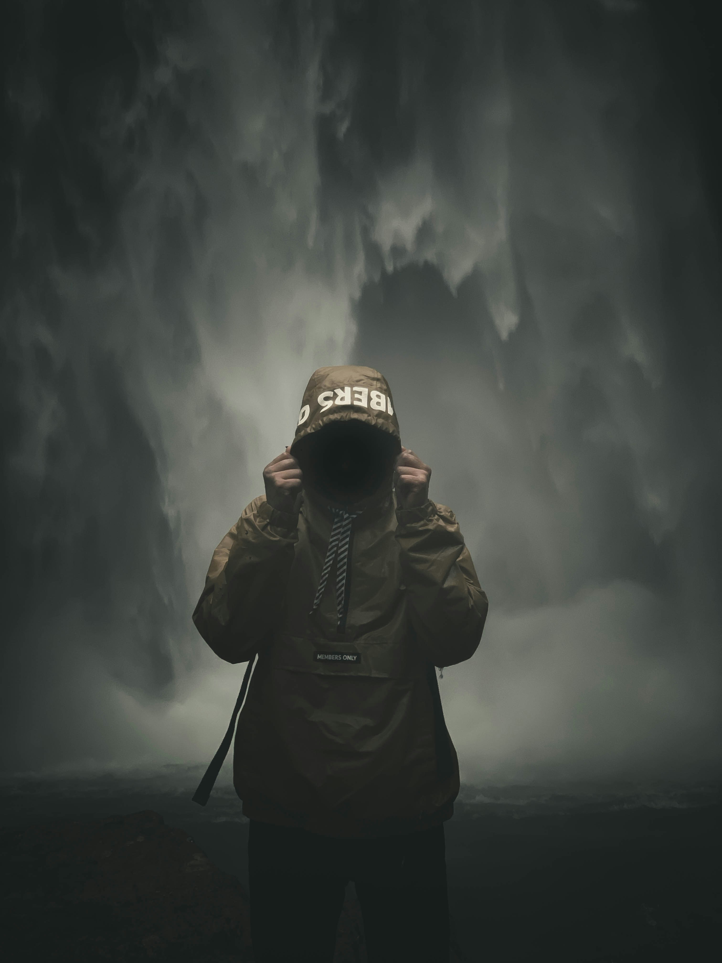 Hooded Silhouette Beneath a Veil of Waterfall Mist