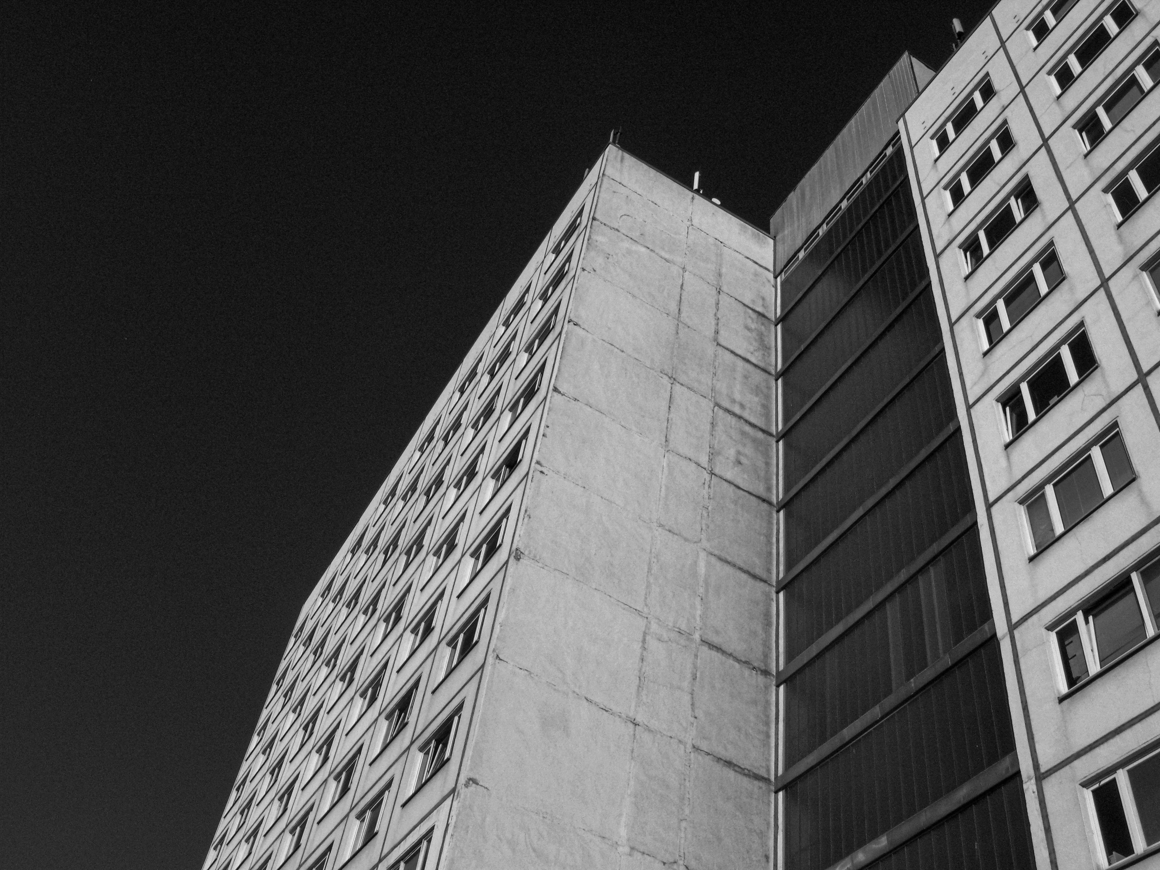 Black and white photograph of a high-rise building with stark lines and contrasting shadows against a dark sky.