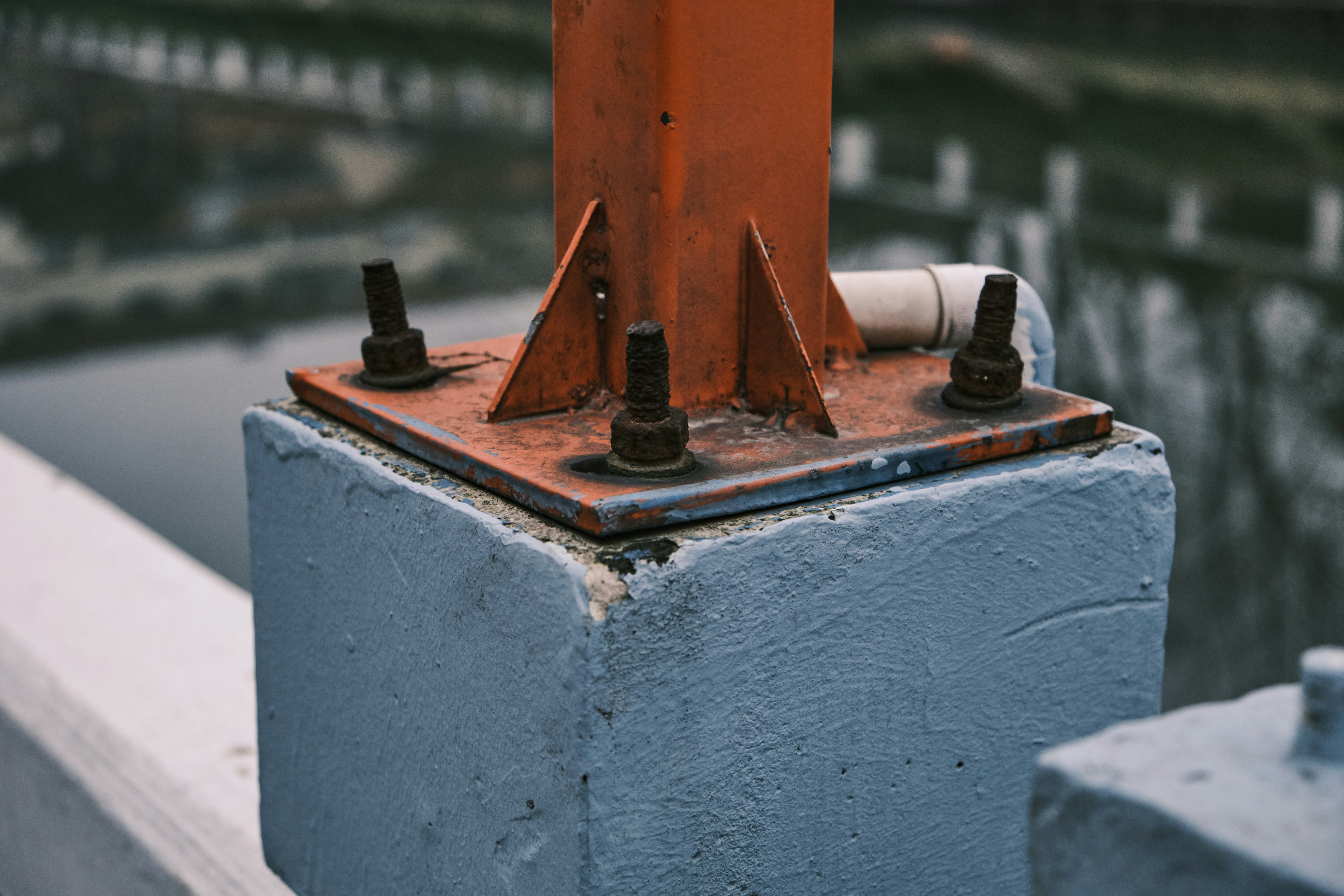 Blue Pier Column with Rusted Bolt Assembly Over Calm Water