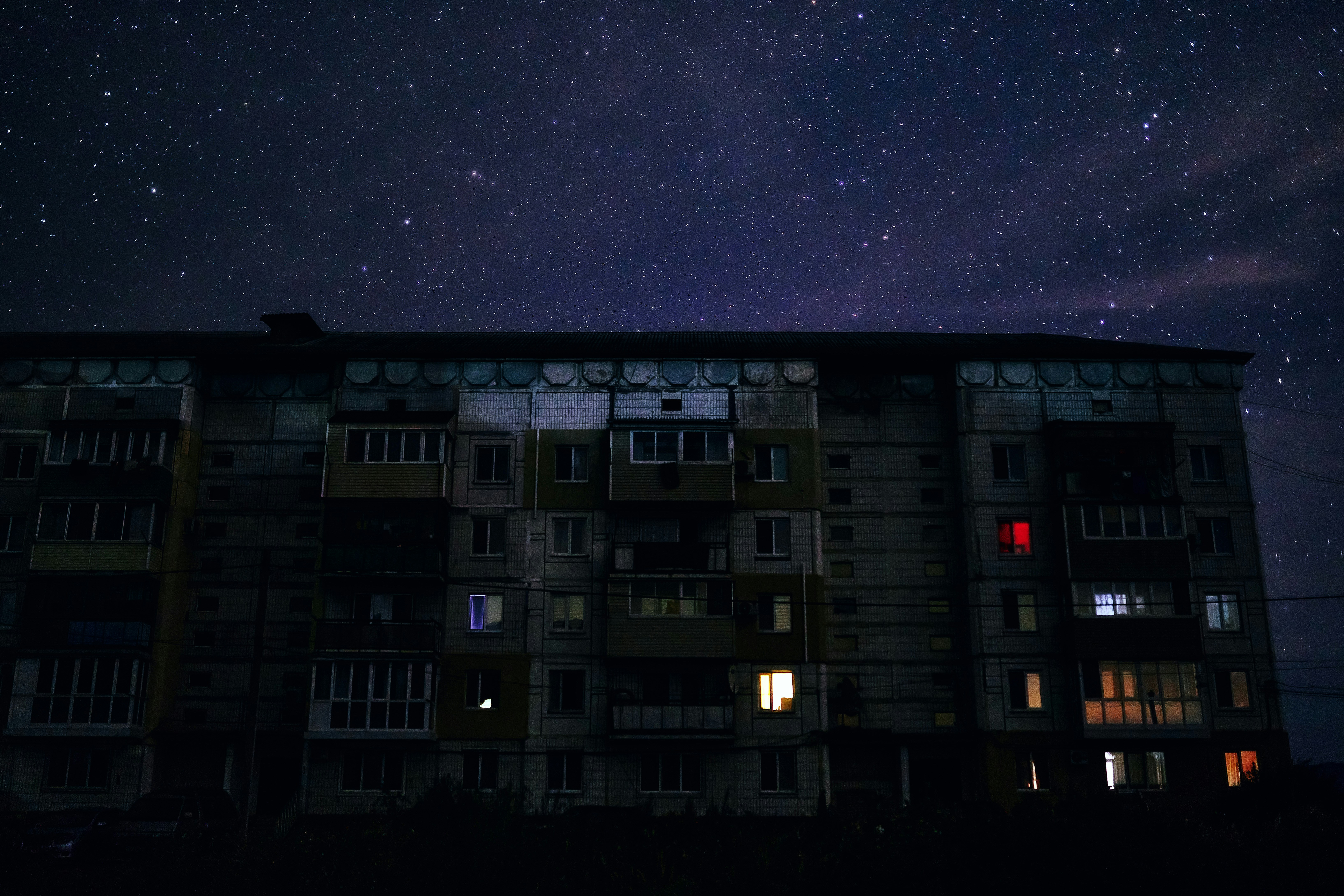 Red Window in a Night-Quiet Block Under a Starfield