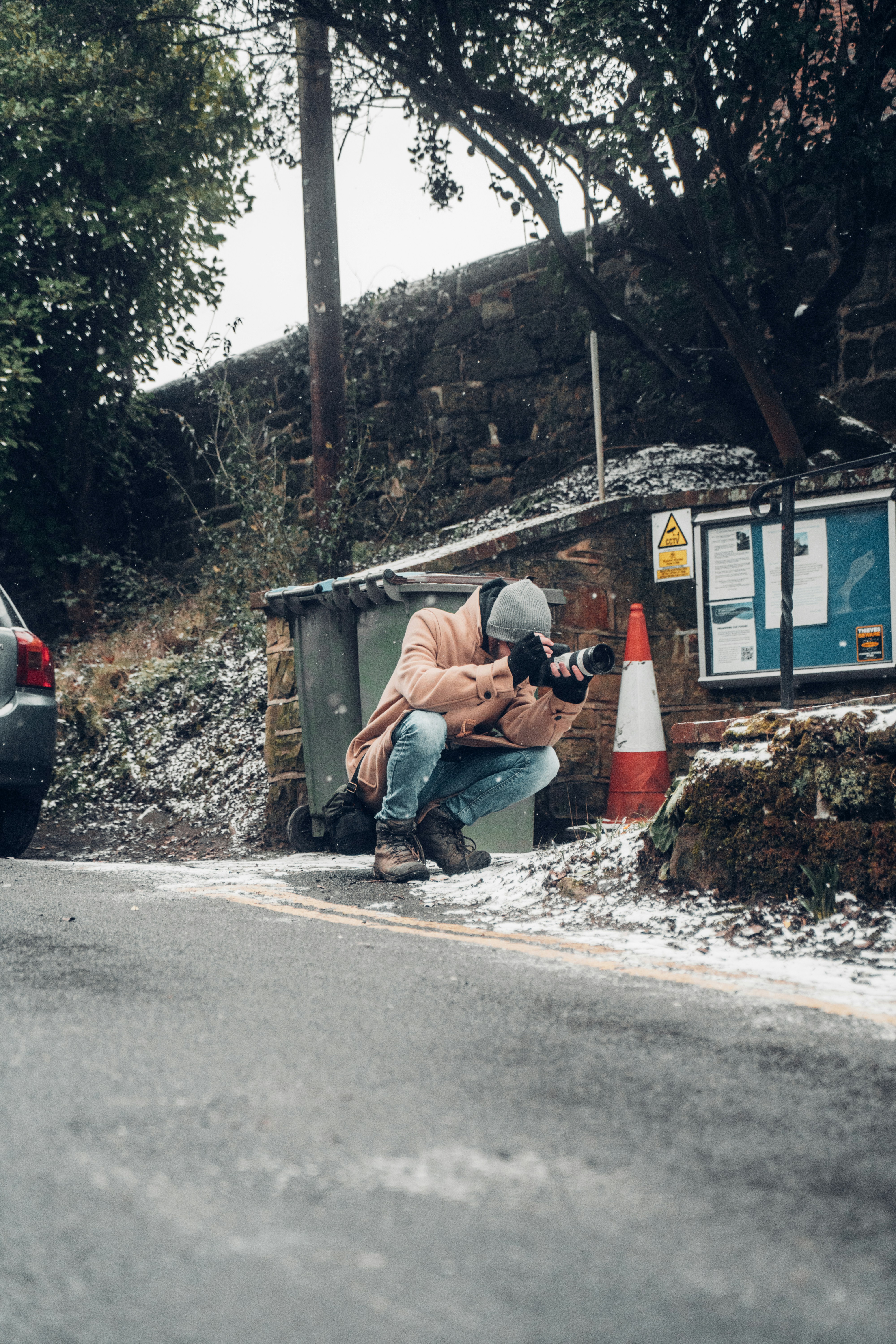 Crouched Street Photographer in Snow-Dusted Urban Scene