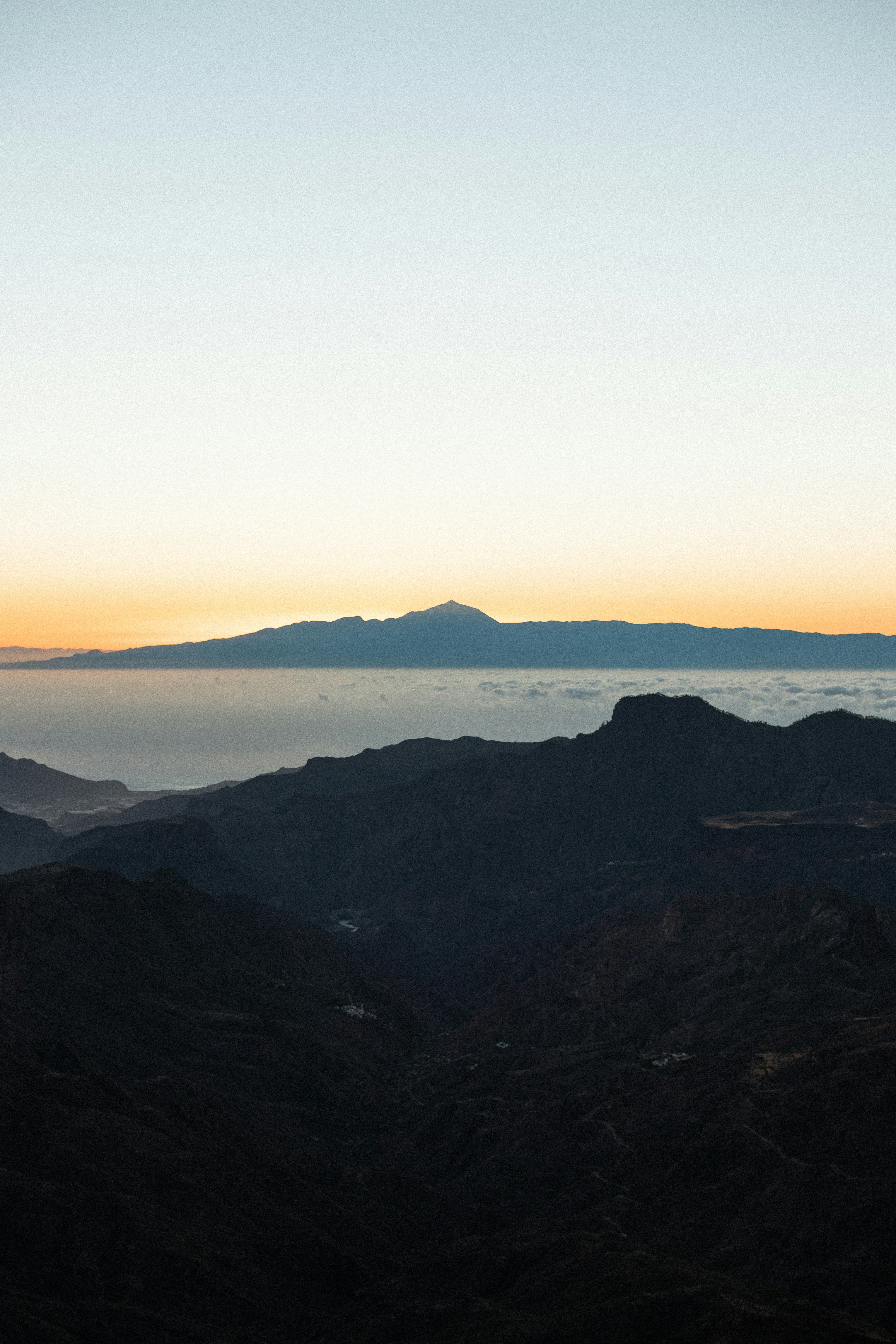 Mountain silhouettes under a gradient sky at dusk with distant peaks visible.