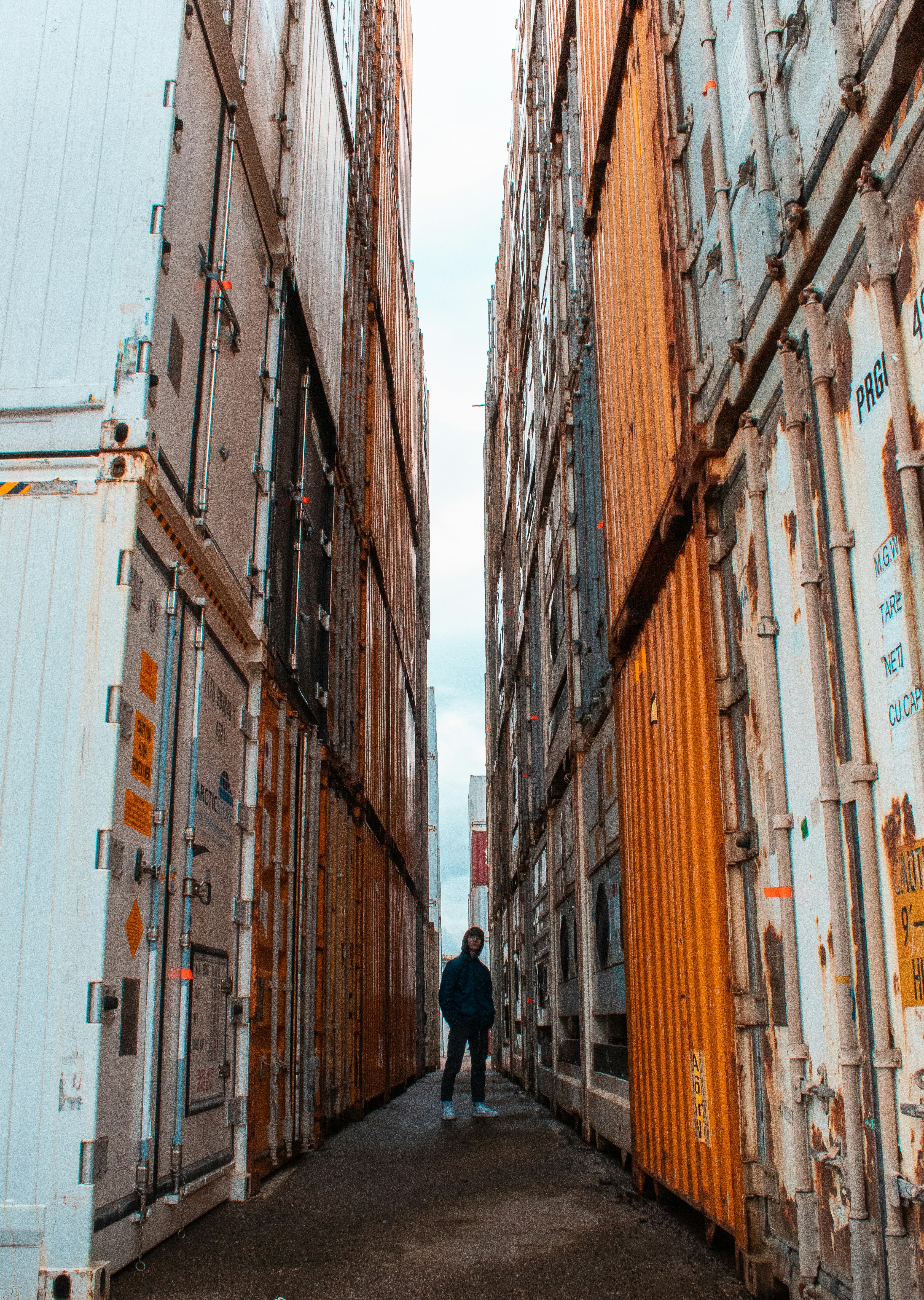 Rust Corridor: A solitary figure at the end of a container-lined canyon
