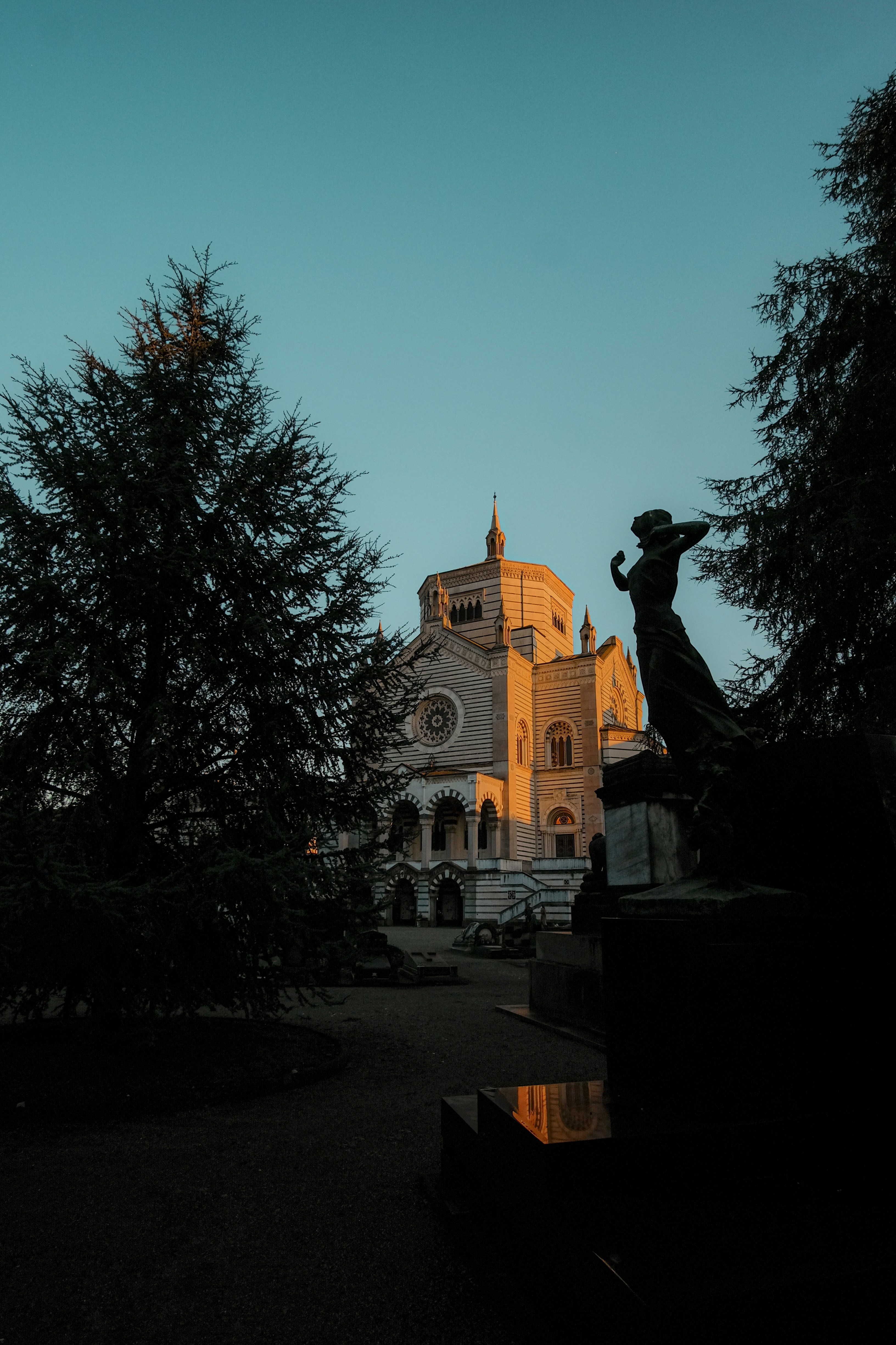 Golden Facade at Dusk: Cathedral Quietly Framed by Trees and Statues