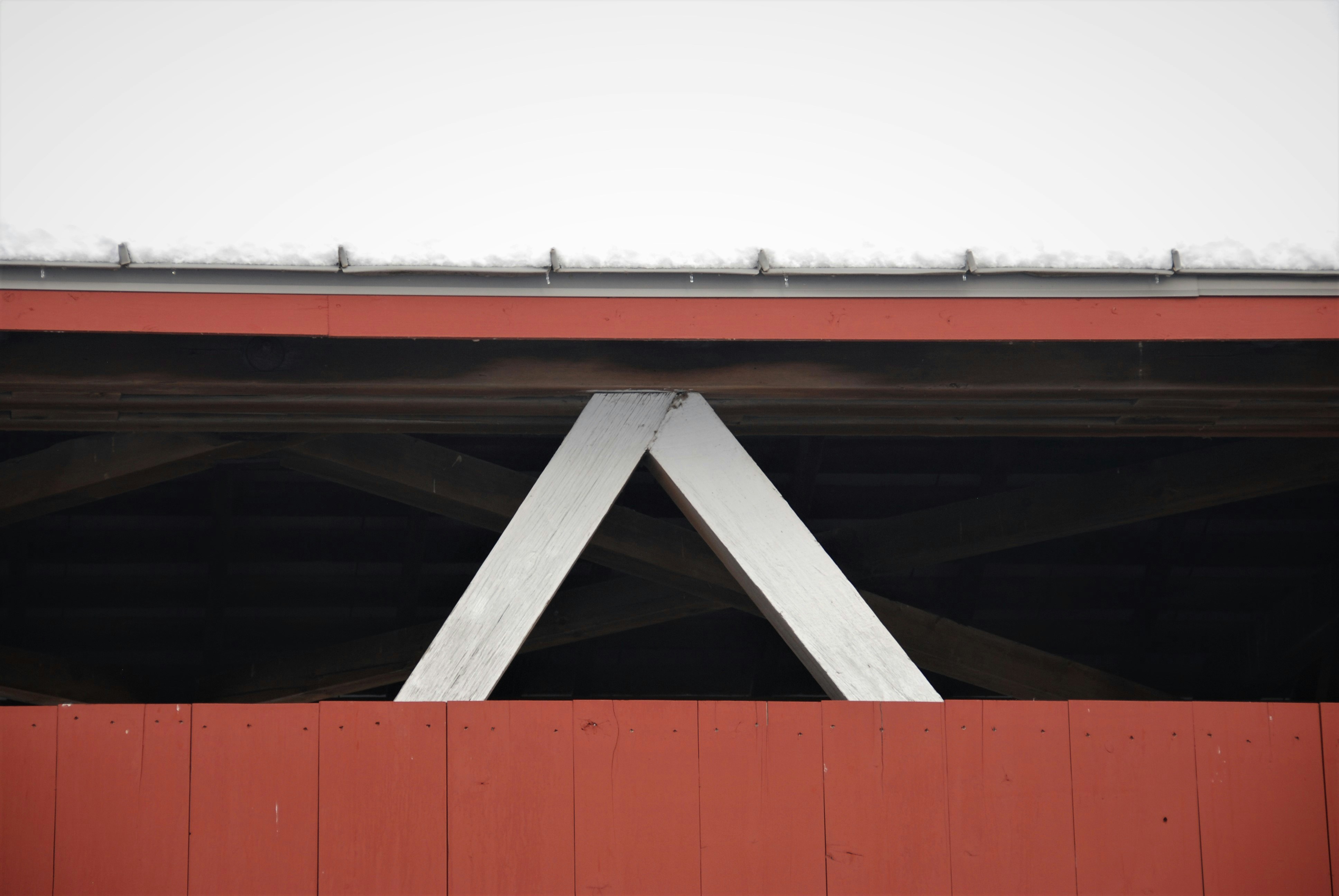 White V on Red Facade: Minimal Geometry of a Barn Crossbeam