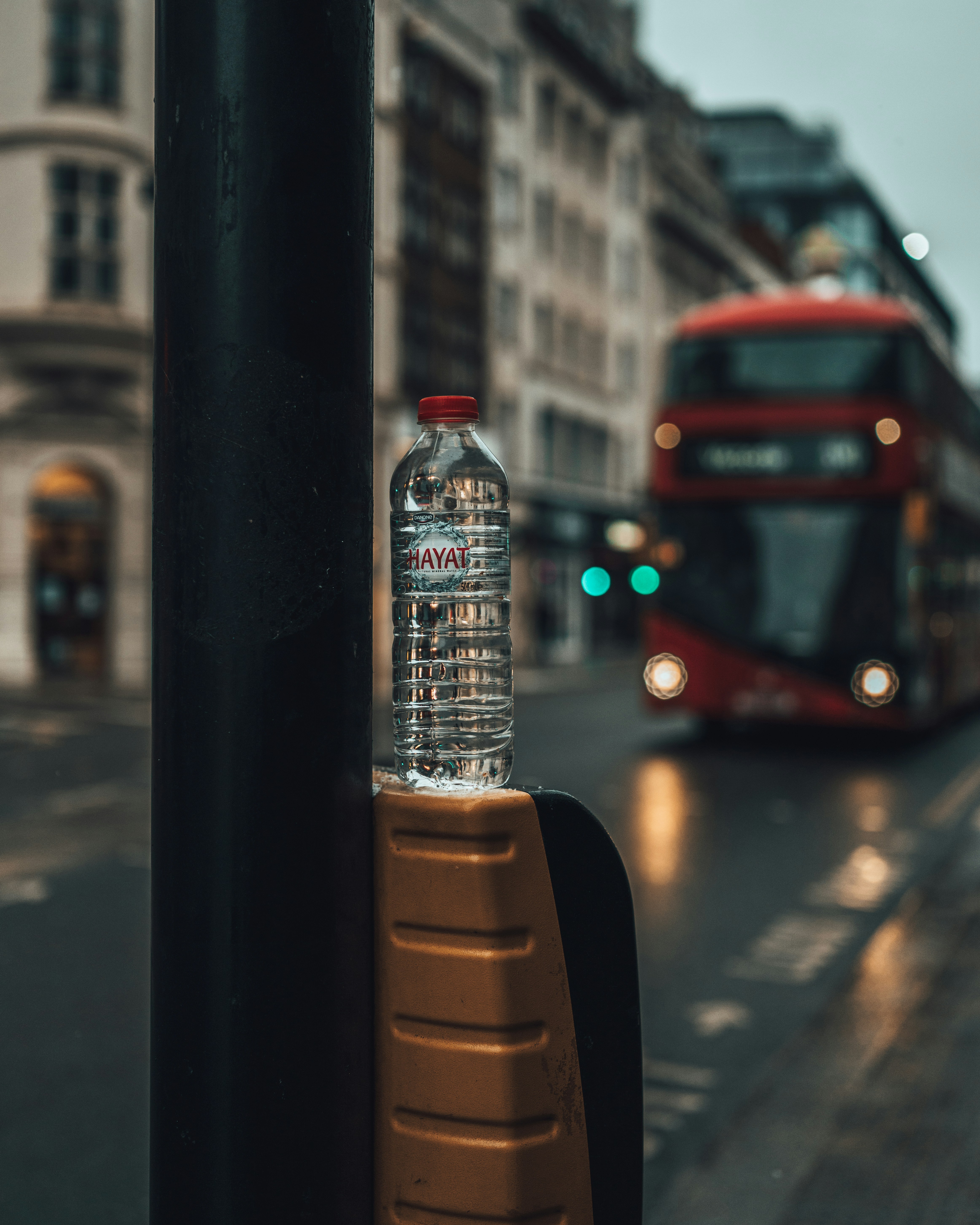 Bottle on a Pedestal, Bus in Blur: Rainy City Street Portrait
