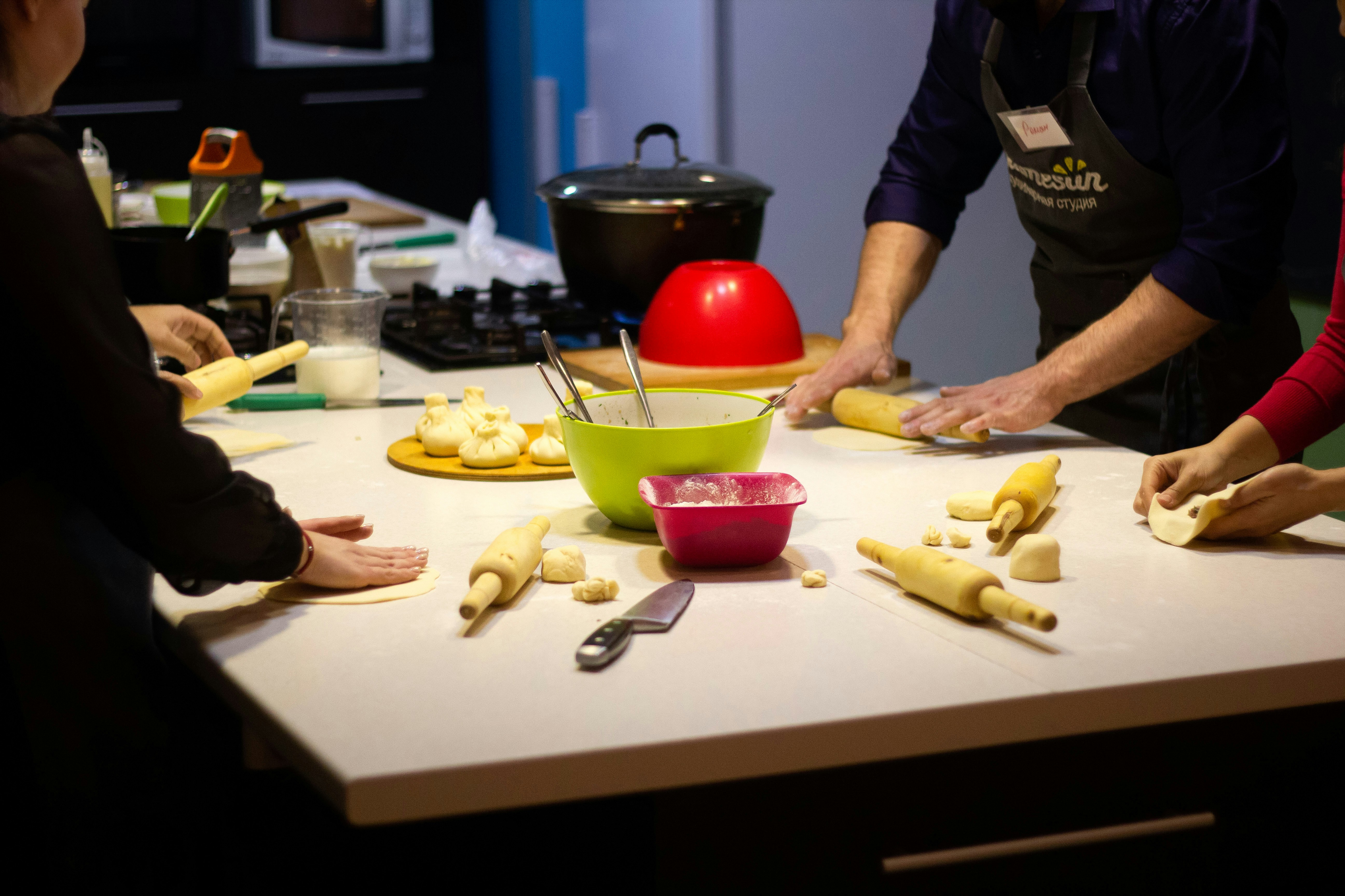 Hands engaged in rolling dough on a kitchen countertop, surrounded by baking tools and ingredients, showcasing a lively cooking session.