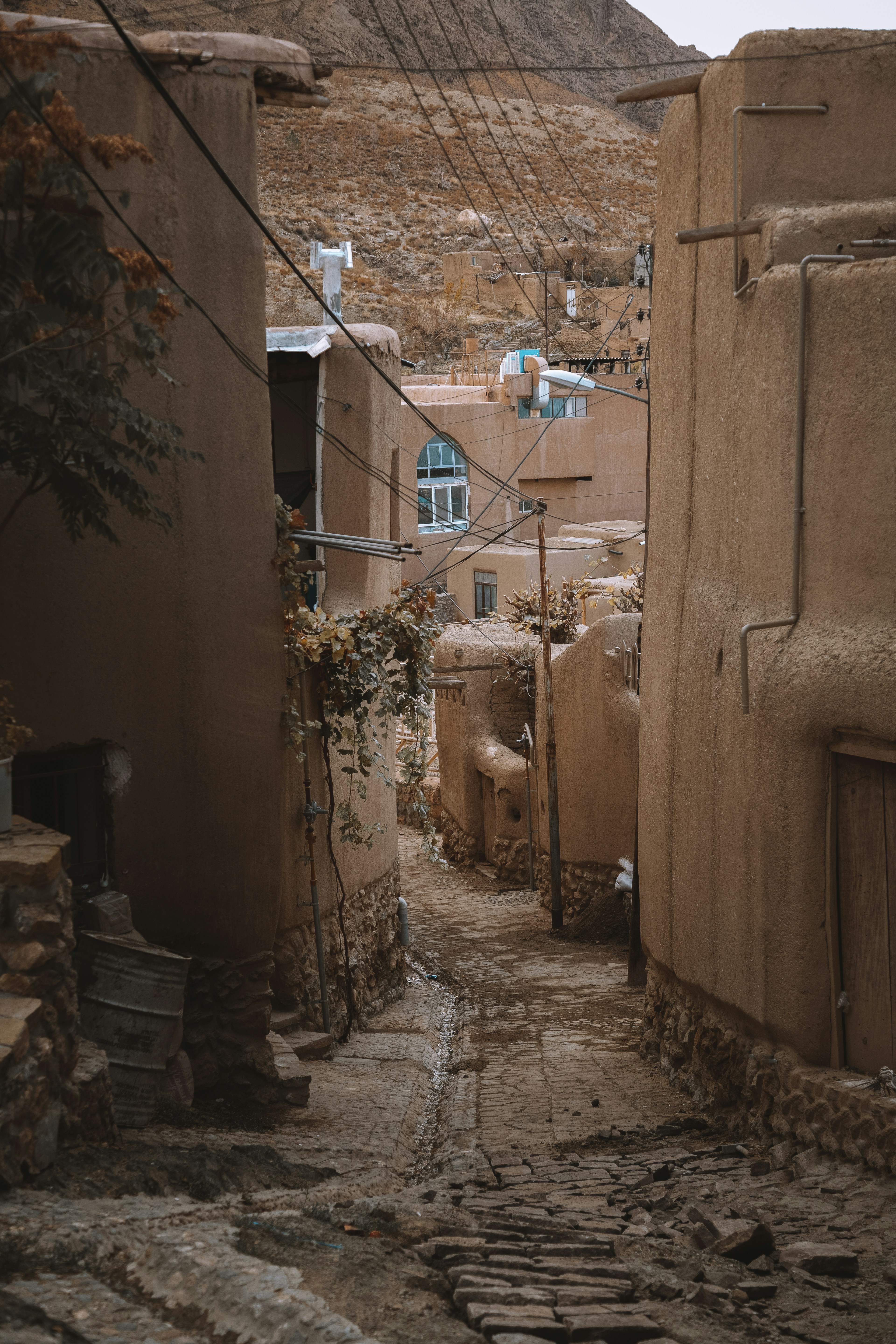 Narrow alleyway winding through traditional earthen structures, showcasing the rustic charm of a historic village.