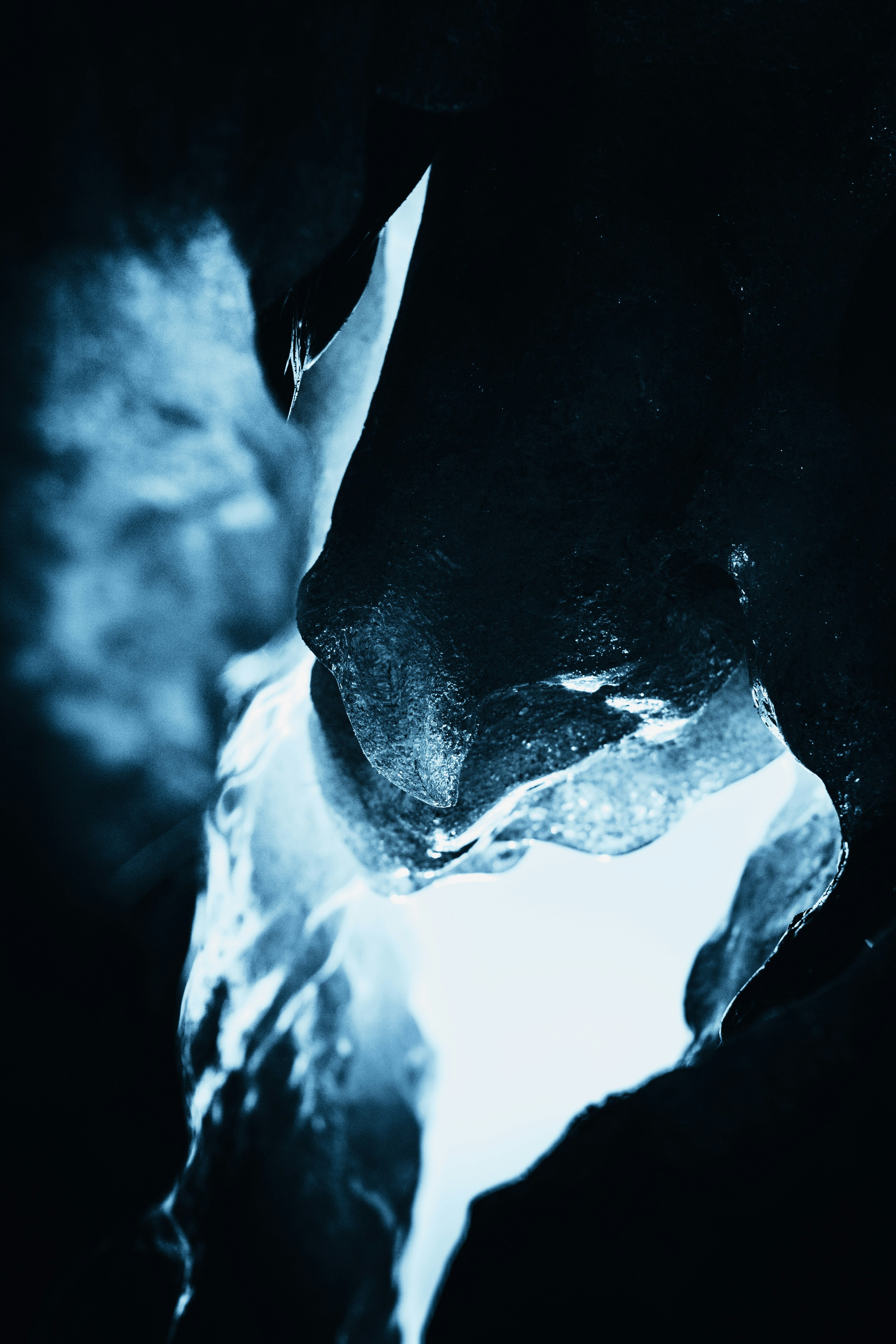 Abstract depiction of light filtering through dark, jagged formations, creating an ethereal glow. Captures the interplay of shadow and illumination.