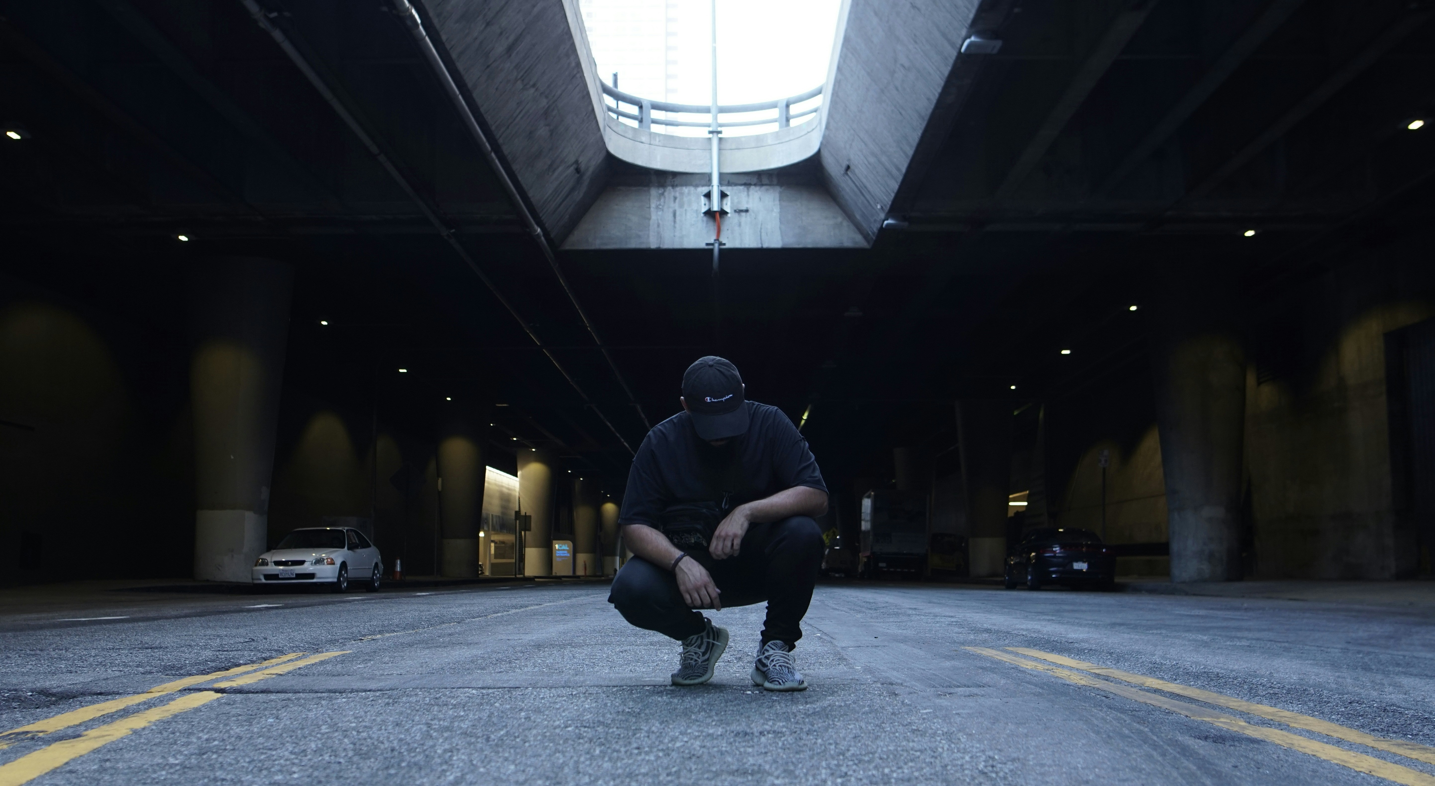 Hunched in the Urban Quiet: A Sole Moment Under the Overhead Light