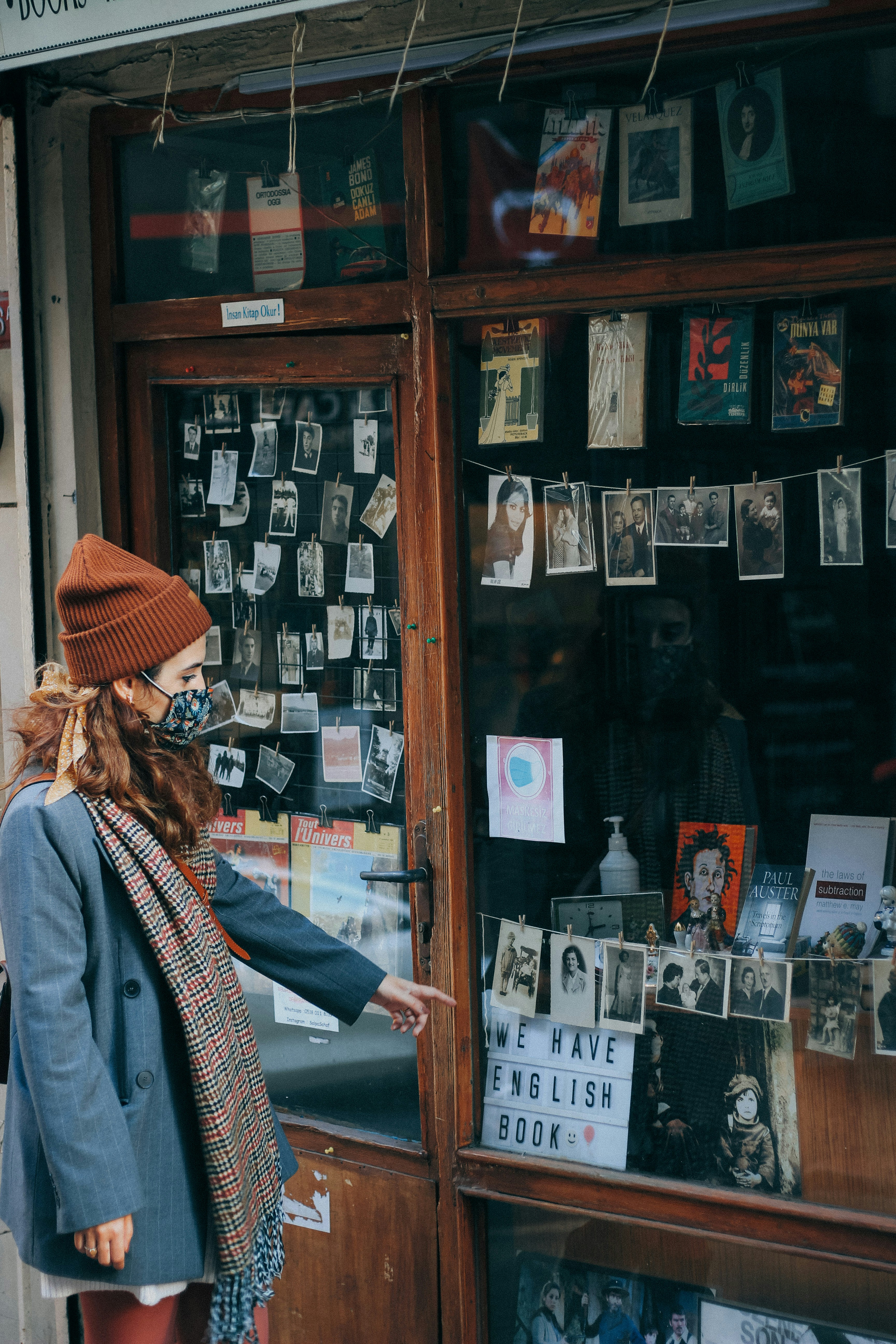 Woman in gray coat and orange knit cap standing in front of store photo ...