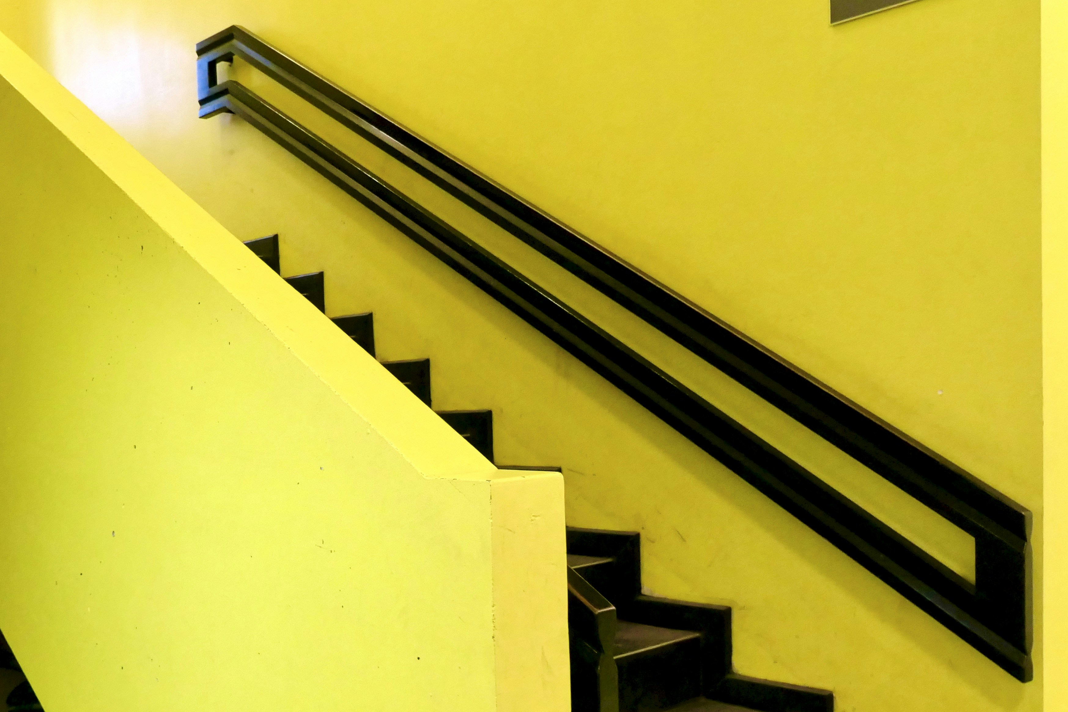 Bright yellow staircase with black railings leading upward, creating a dynamic visual path.