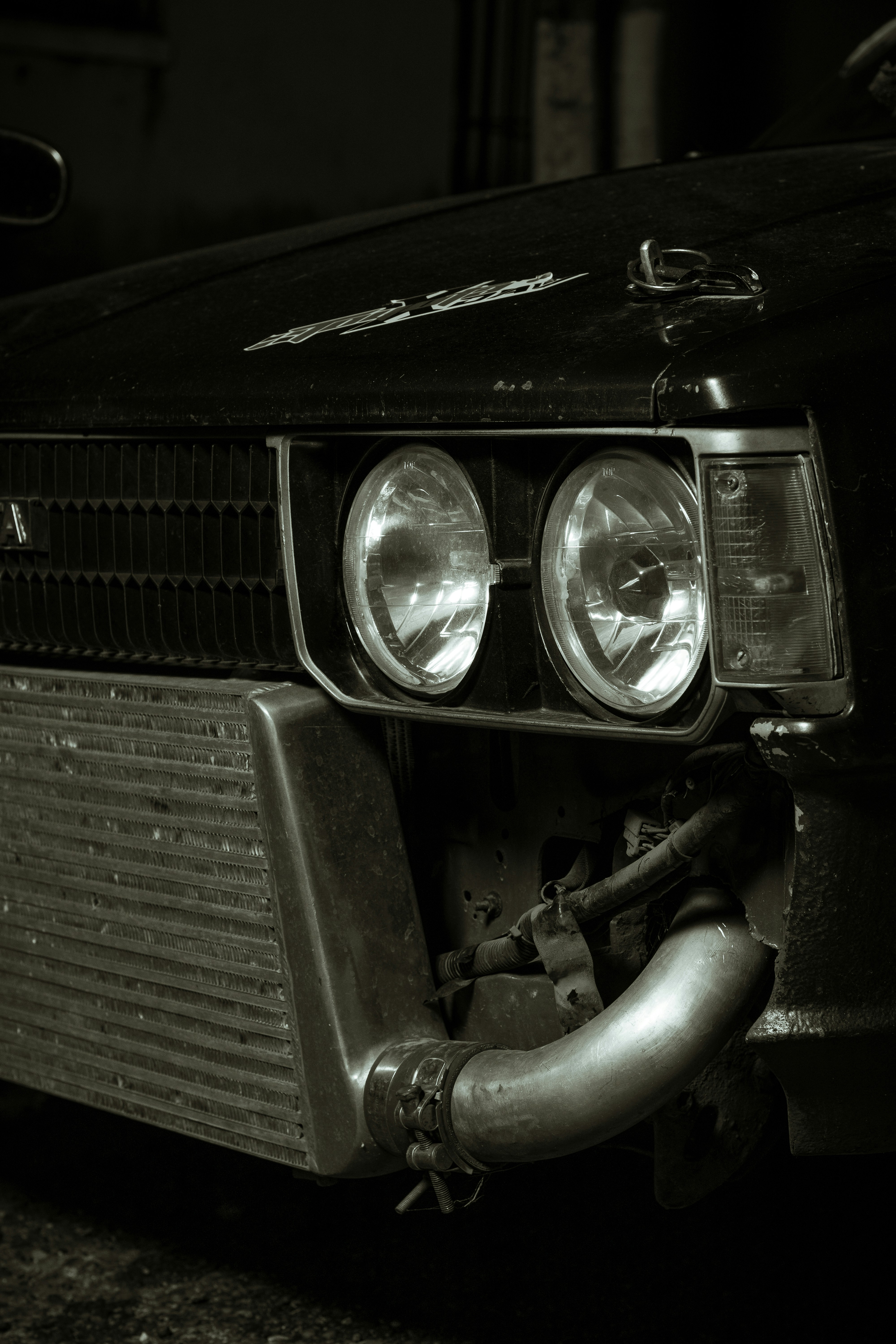 Close-up of a classic car's front end, showcasing its headlights and intricate detailing, highlighting the blend of nostalgia and mechanical artistry.