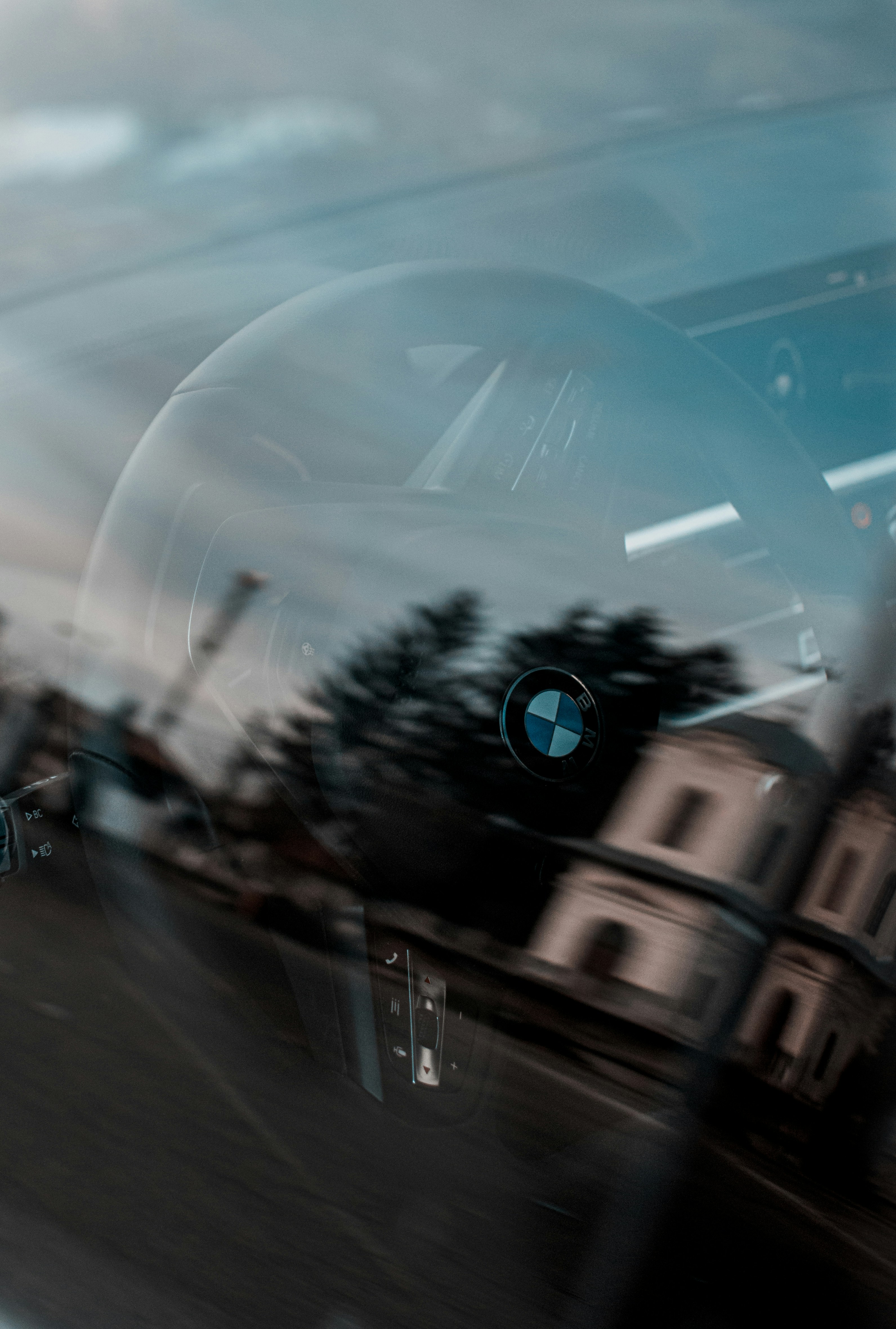 Veiled Velocity: The BMW emblem emerging through glass reflections