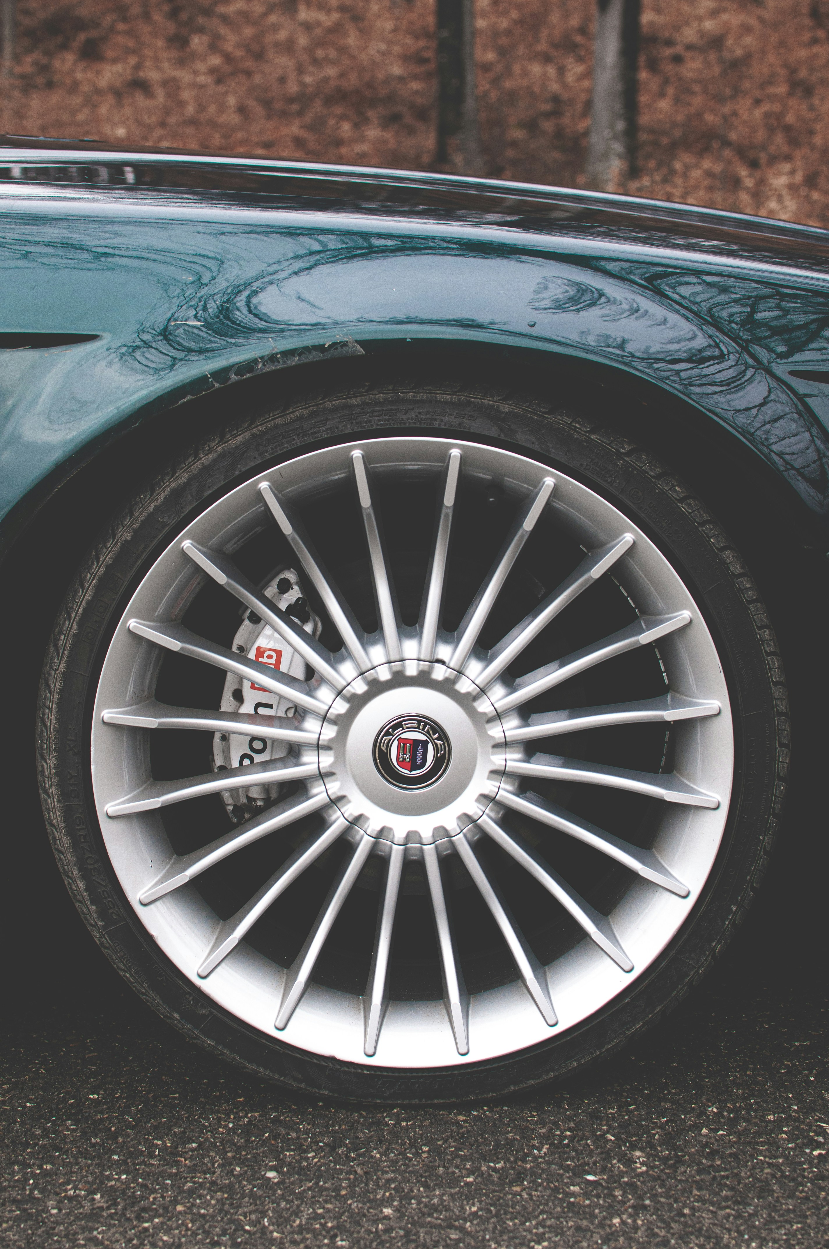 Radial Precision: Teal Sports Car Wheel with Intricate Alloy Spokes