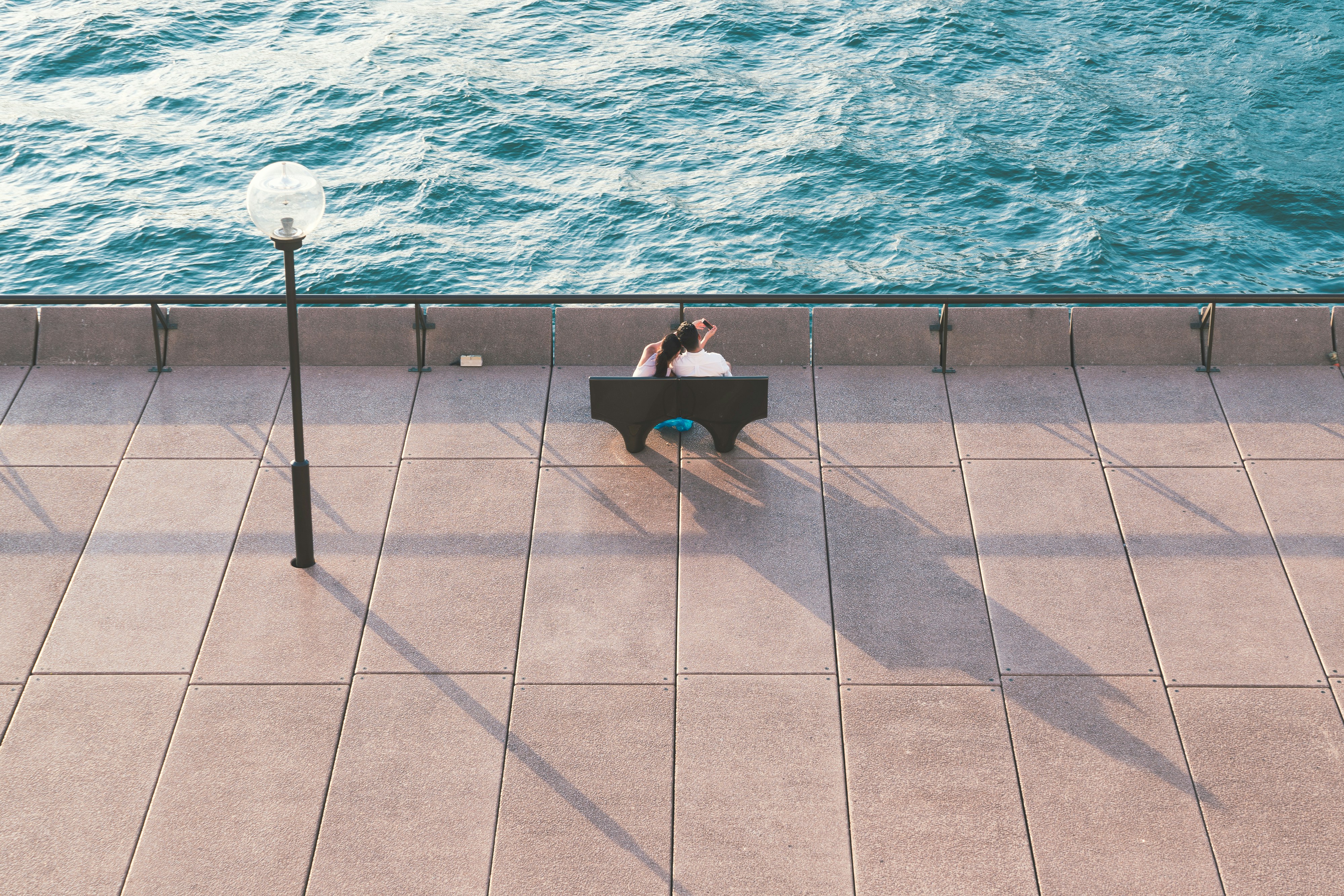 Seaside Quiet: a lone reader on a sunlit pier bench