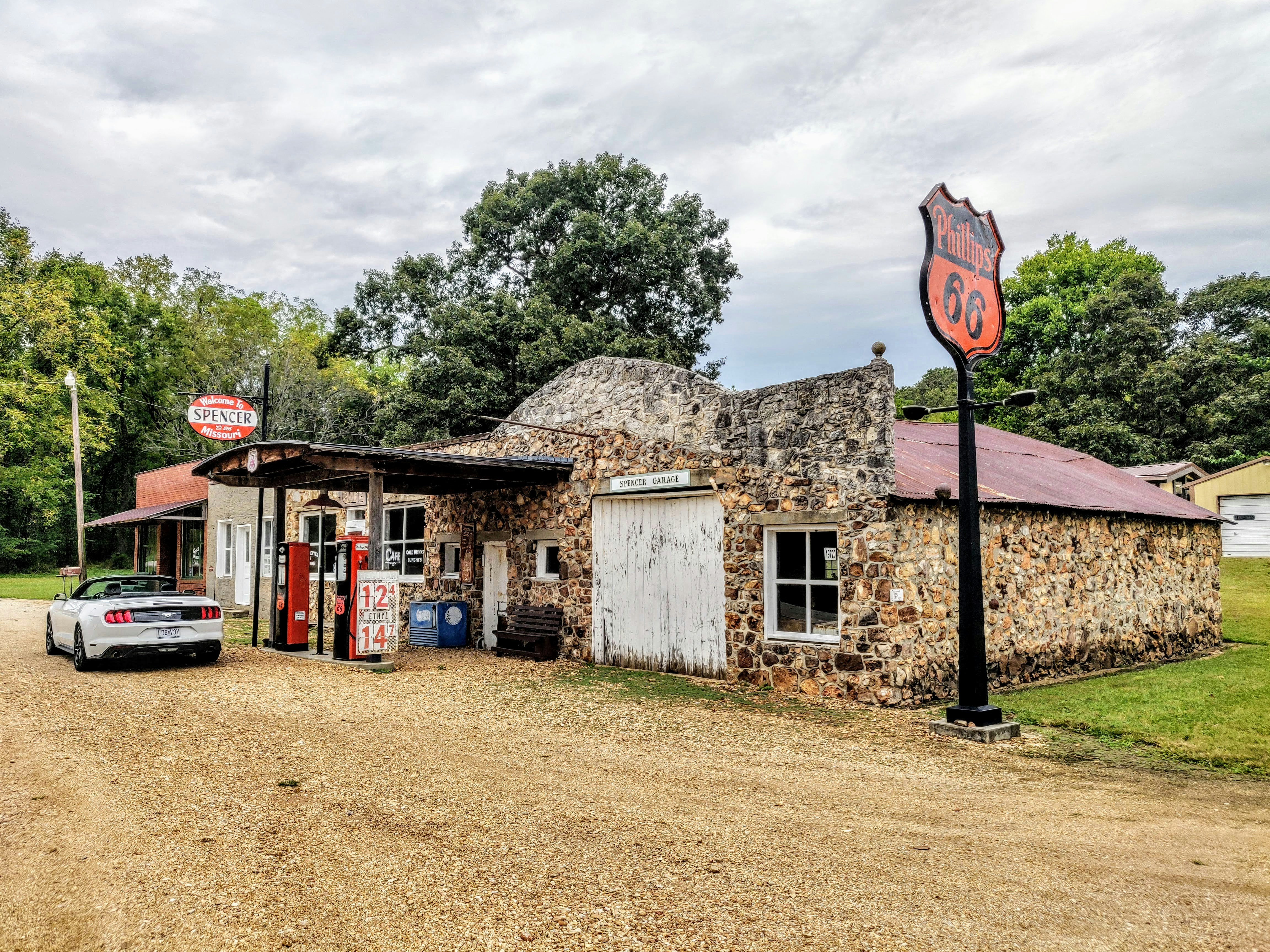 Historic stone gas station with vintage pumps and signage on a rural road.