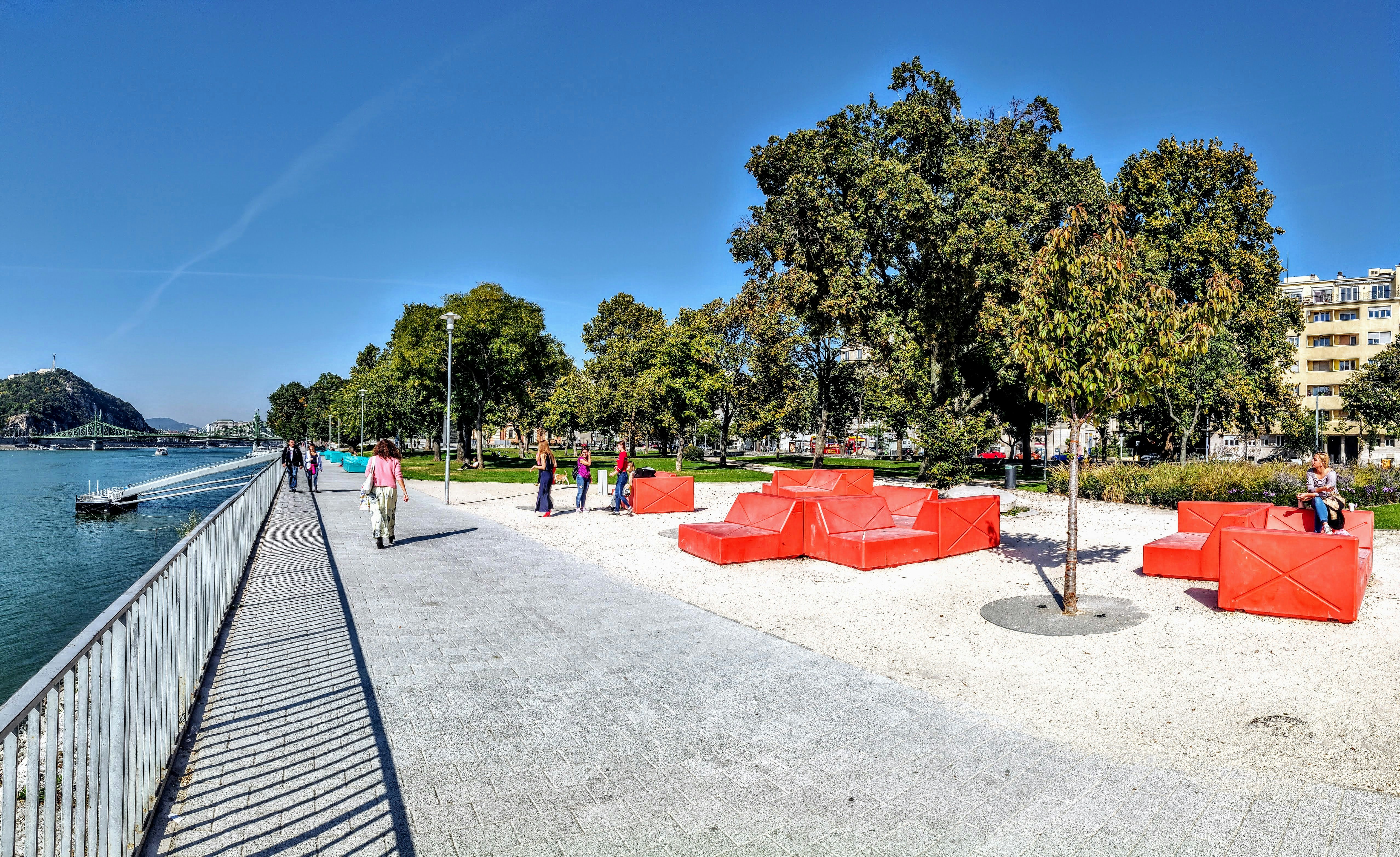 Sunlit Seaside Promenade with Red Modern Seating