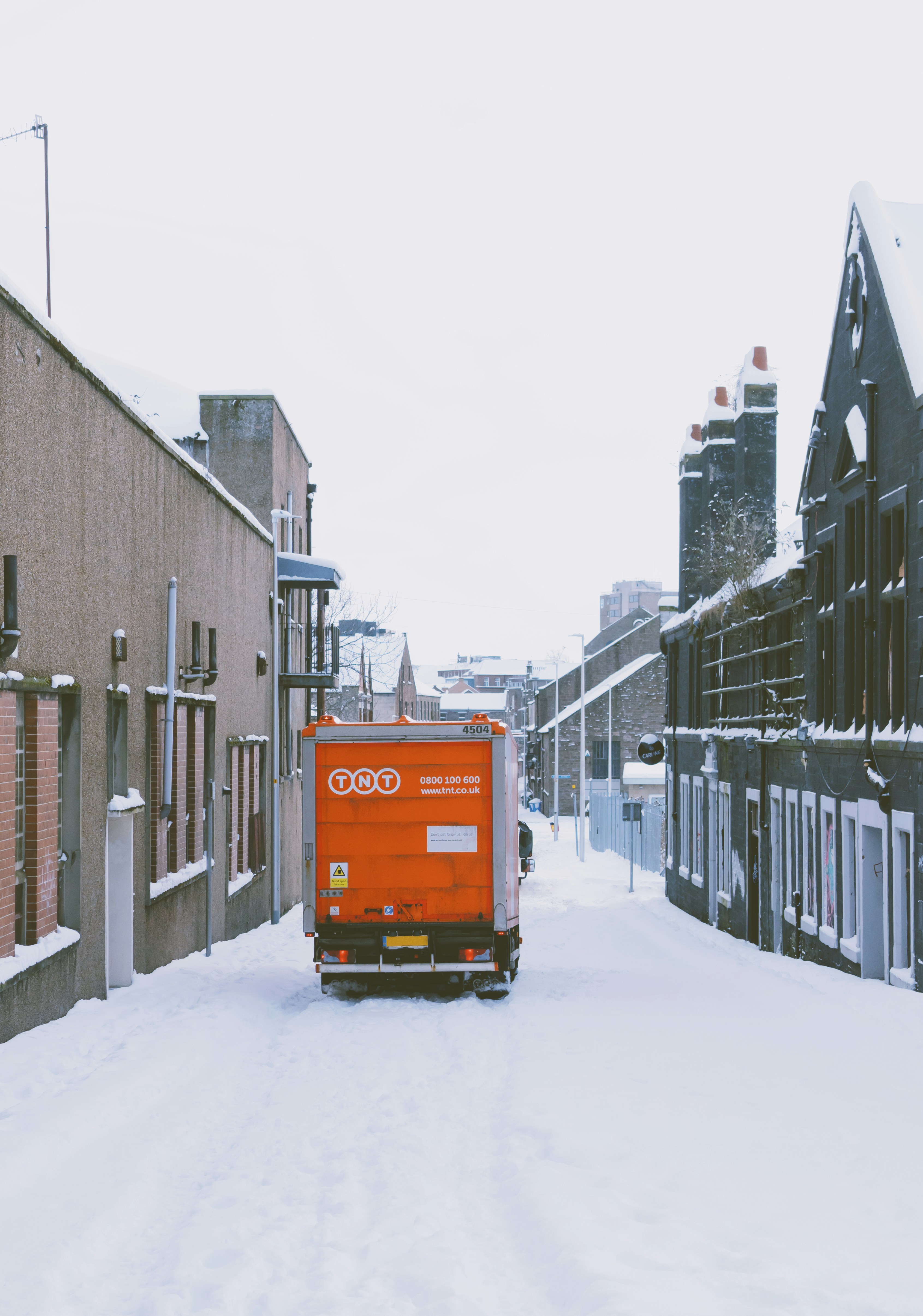 Orange Truck in a Snowbound Urban Alley