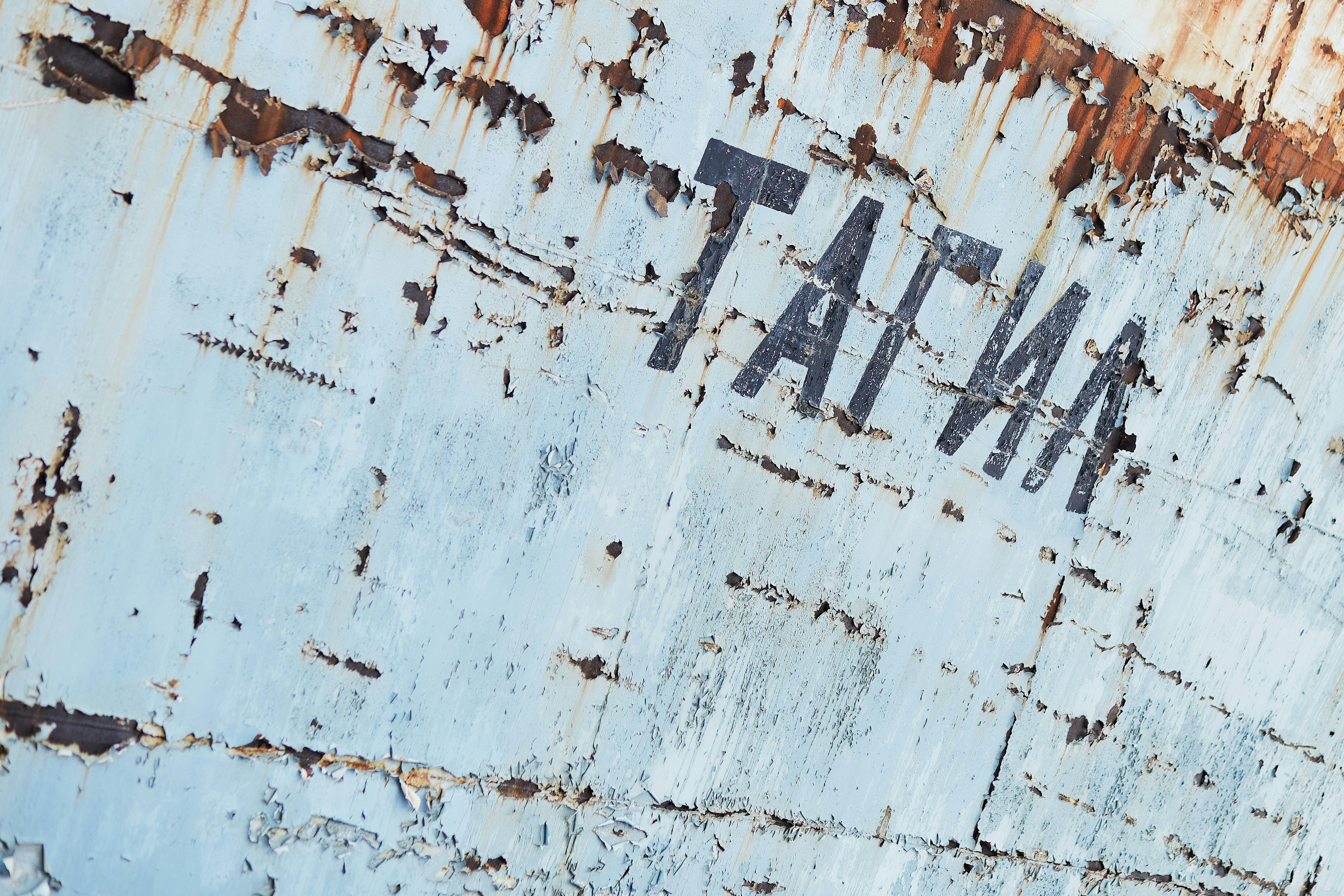 Rusted Script on a Sky-Blue Metal Panel