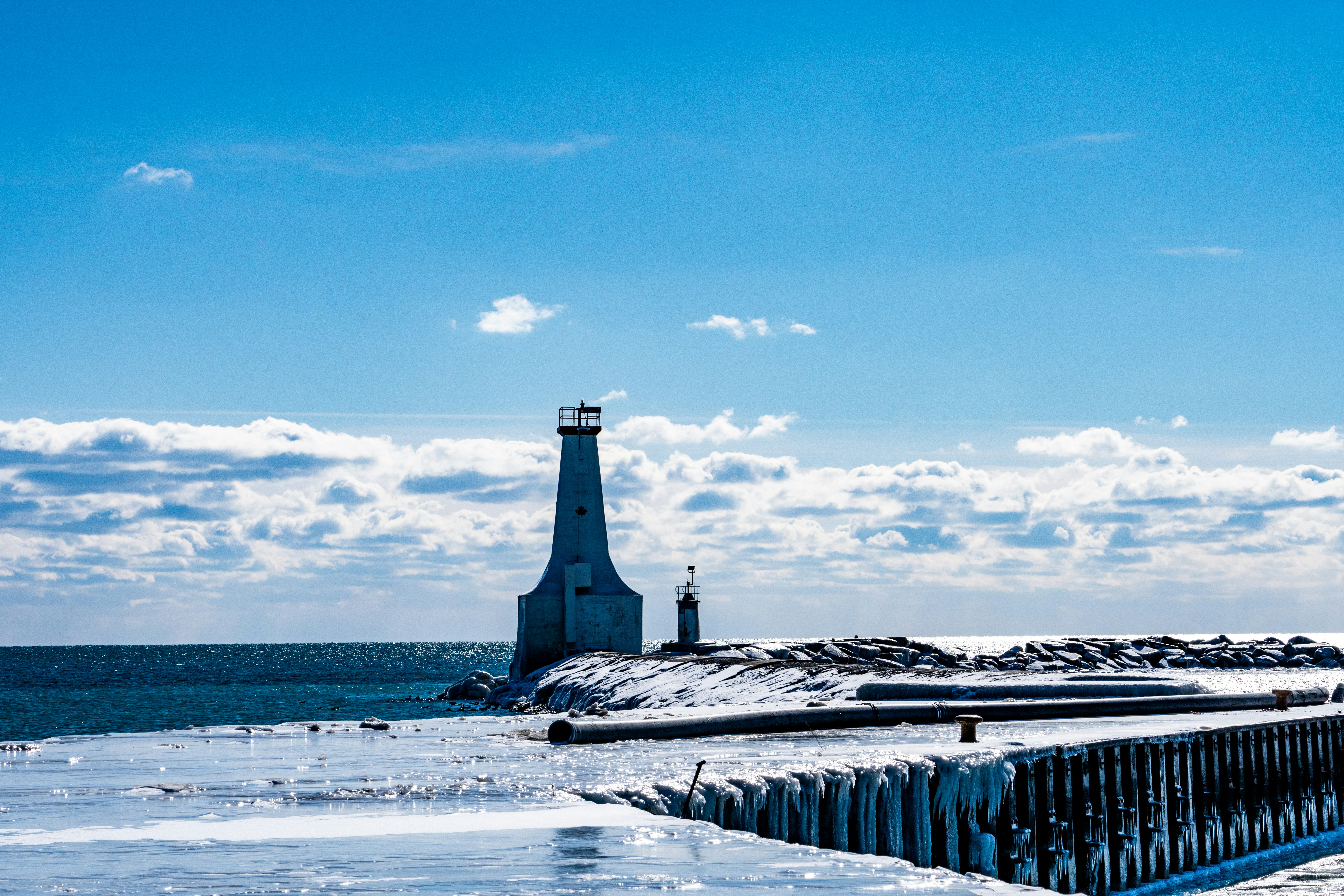 Snow-Dusted Lighthouse at the Edge of a Frozen Breakwater