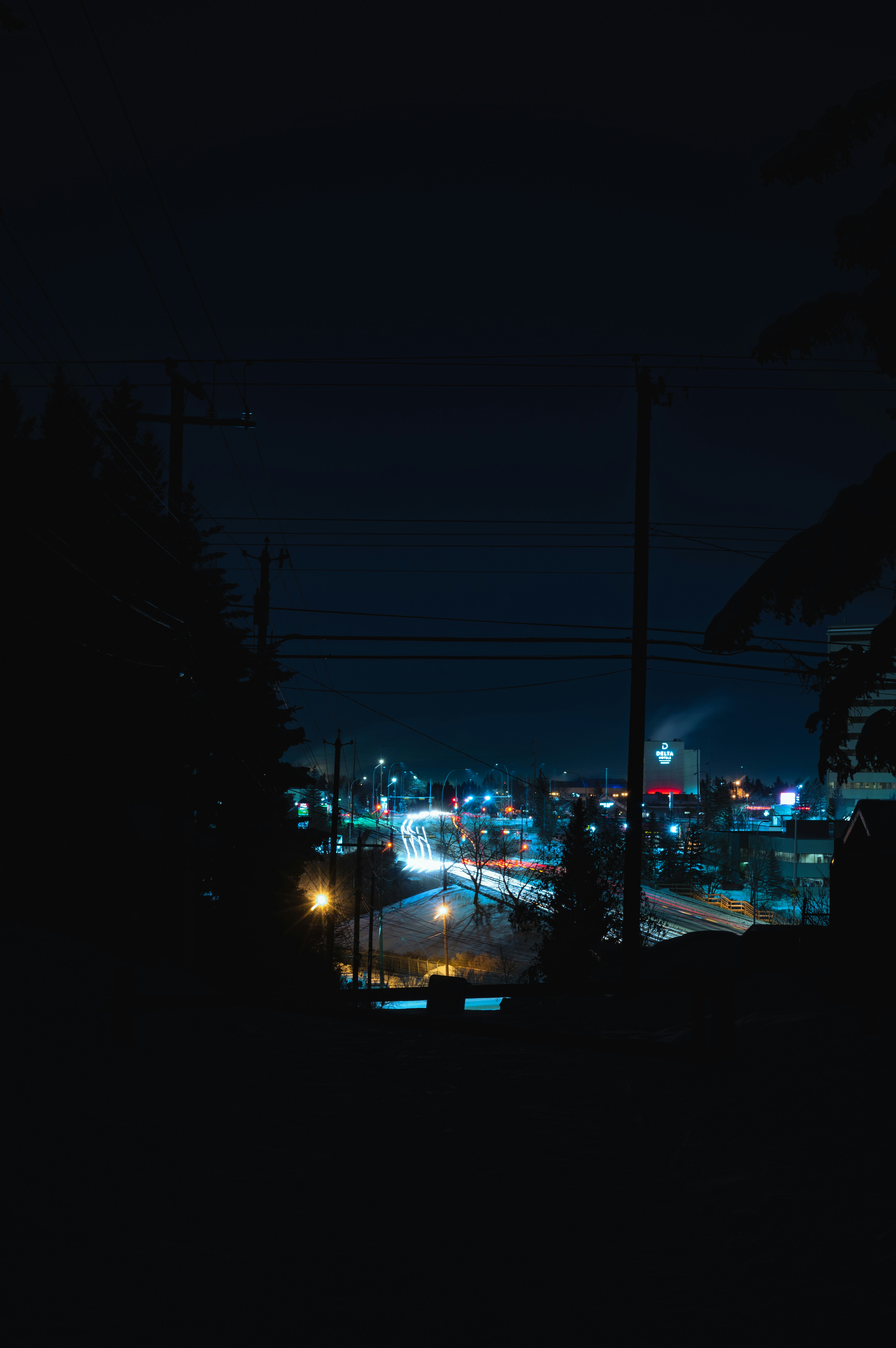 Midnight Highway Glow: Blue-Neon Streetlines over a Quiet Town