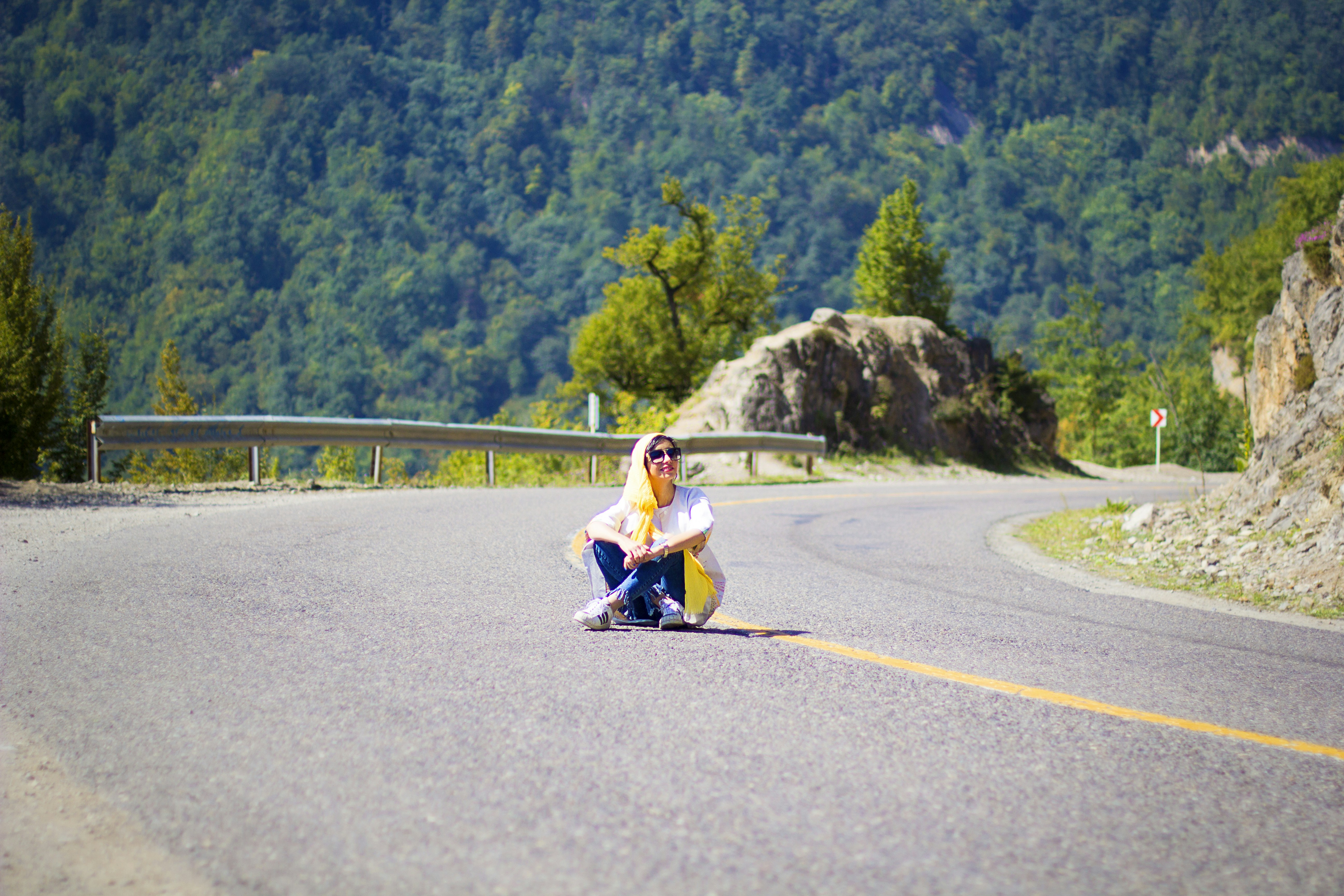 man in white shirt riding on black and white bicycle on gray asphalt road during daytime