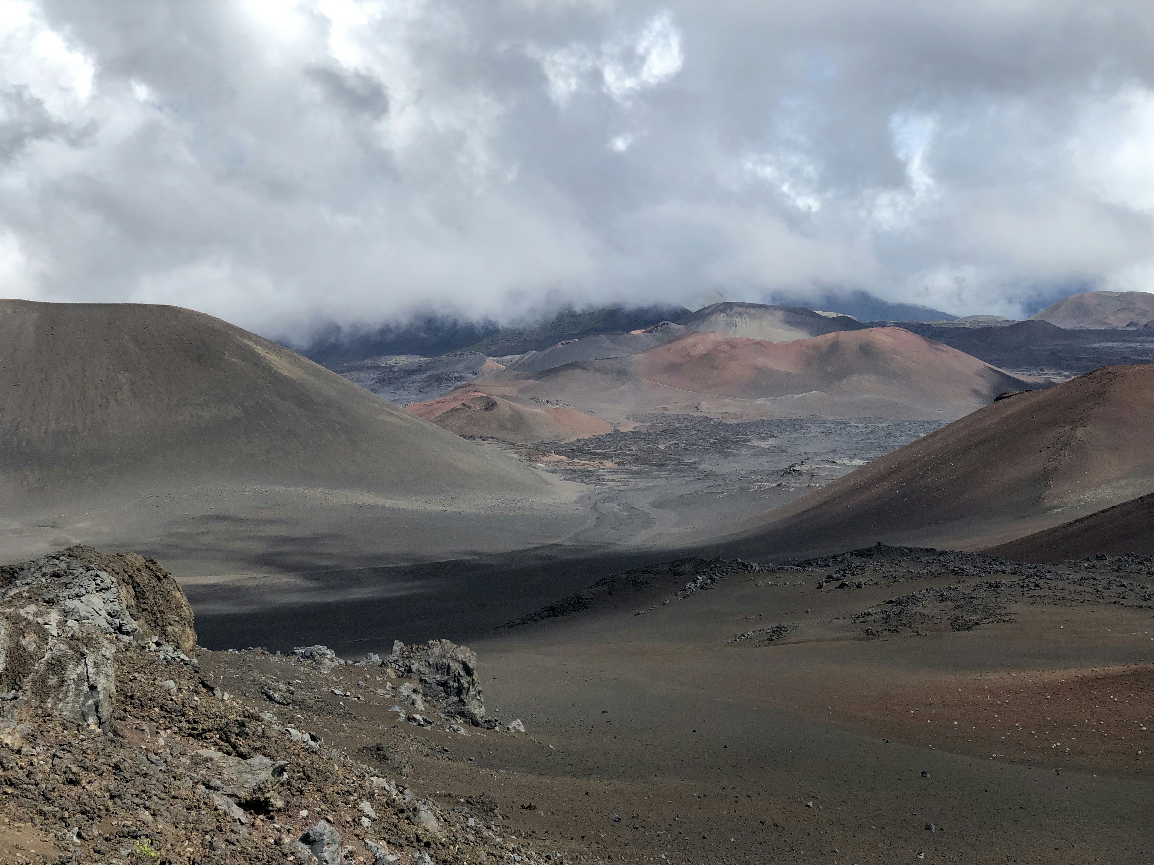 Volcanic terrain beneath a dramatic cloud-filled sky in Haleakalā National Park.