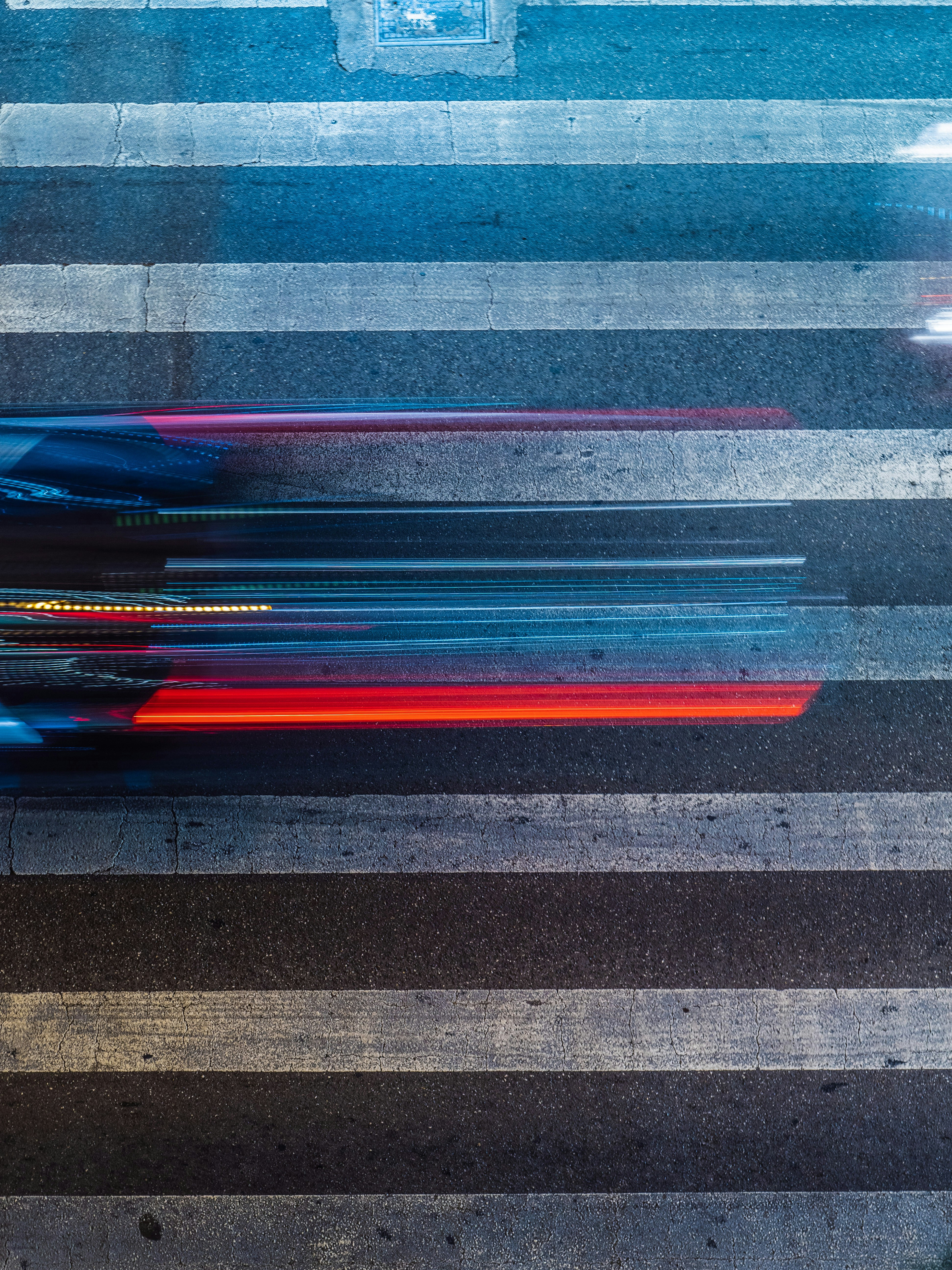 Crosswalk in Motion: Neon Light Trails Sweep the Painted Stripes