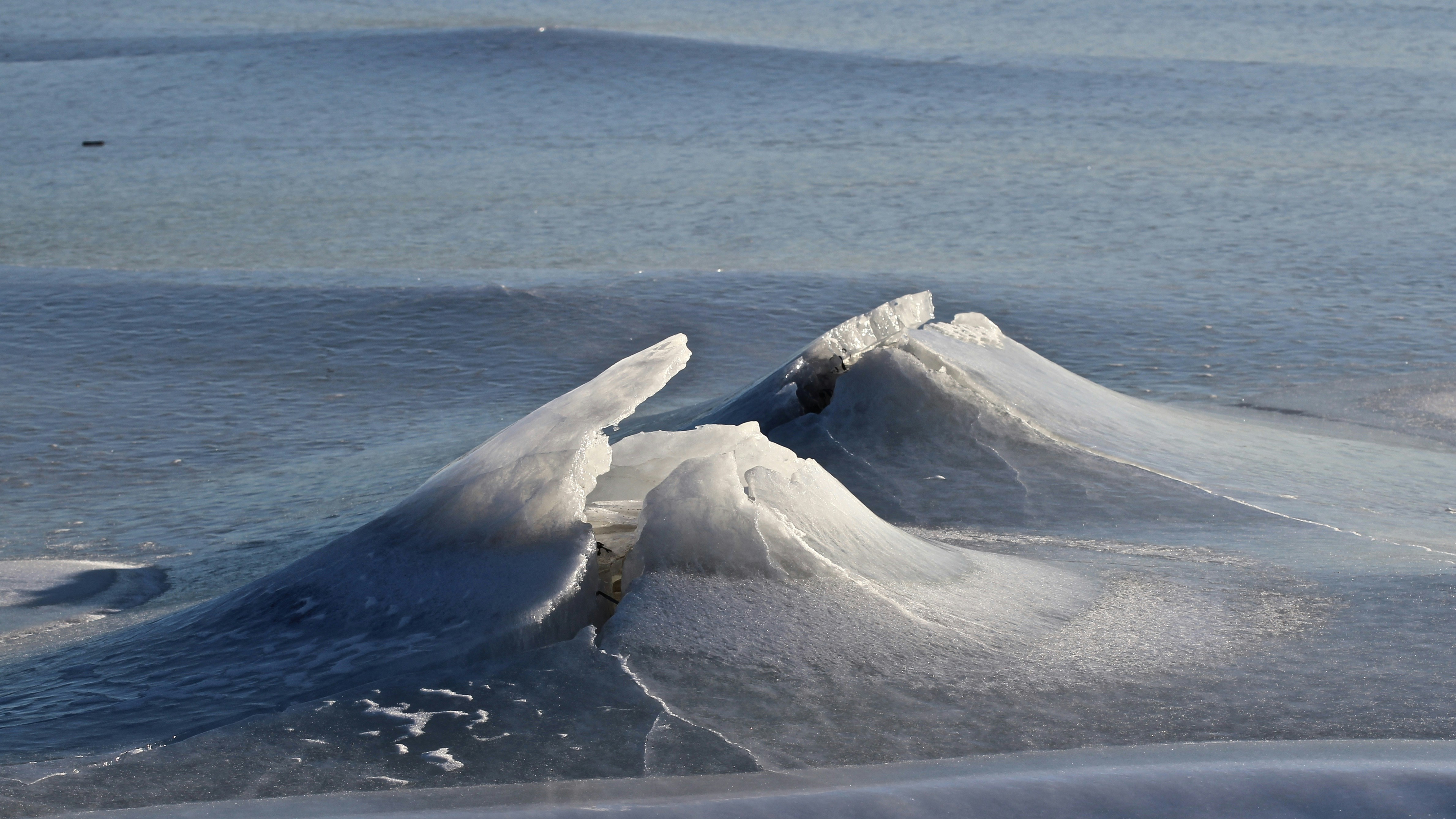 Intricate ice formations jutting from a frozen surface, glistening under natural light. The scene captures the serene beauty of winter's artistry.
