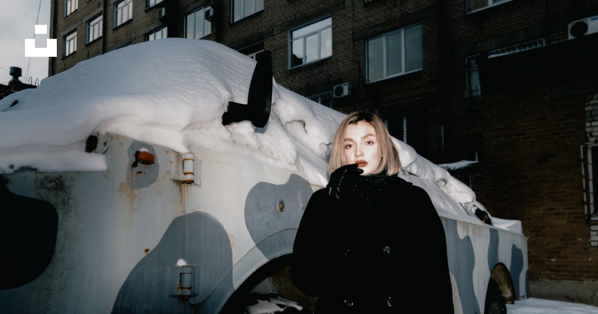 昼間、白と黒の列車の近くの雪に覆われた地面に立つ黒いコートの女性の写真 Unsplashの灰色の無料画像