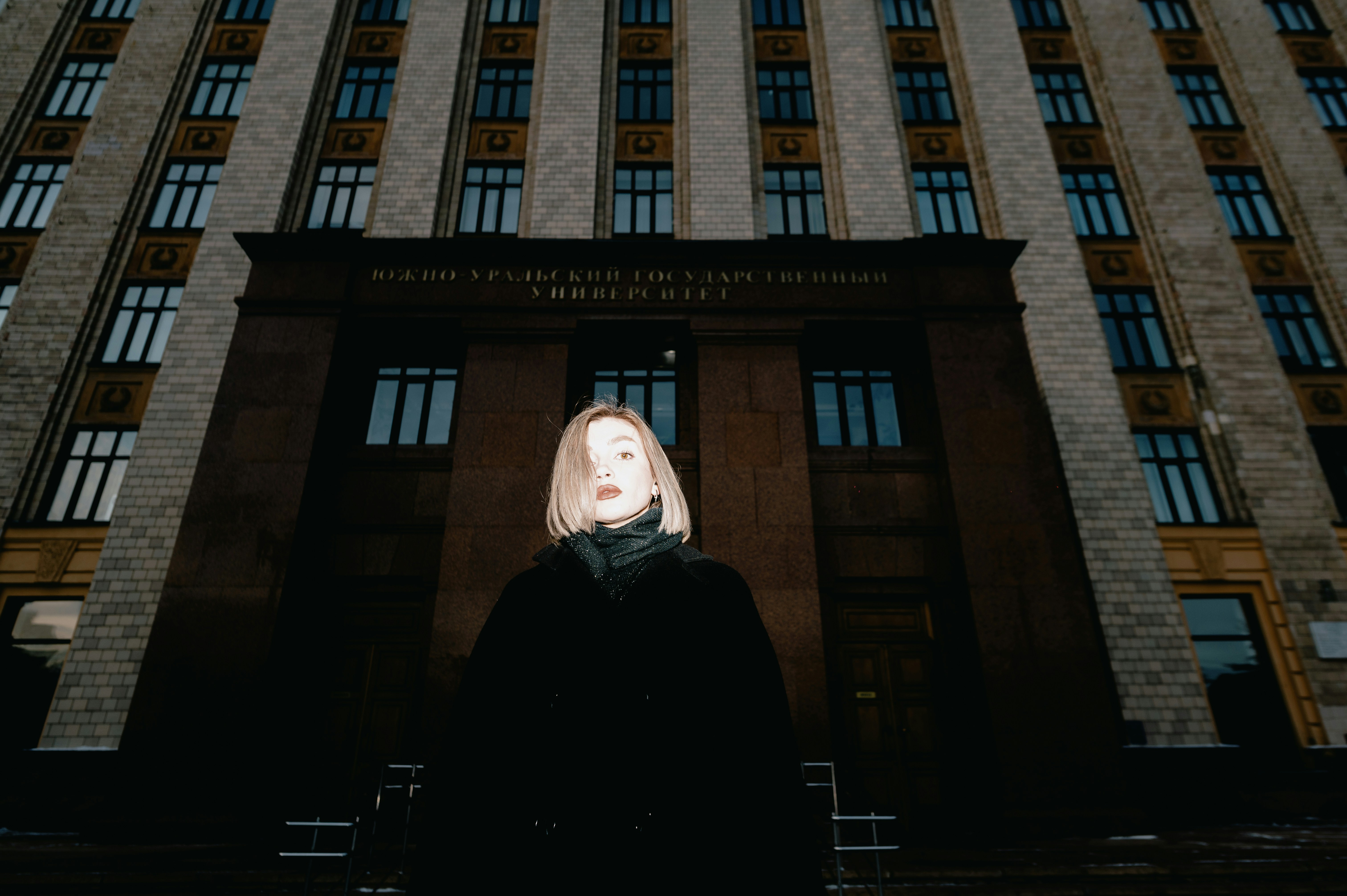 Woman in black coat standing in front of brown building photo – Free ...