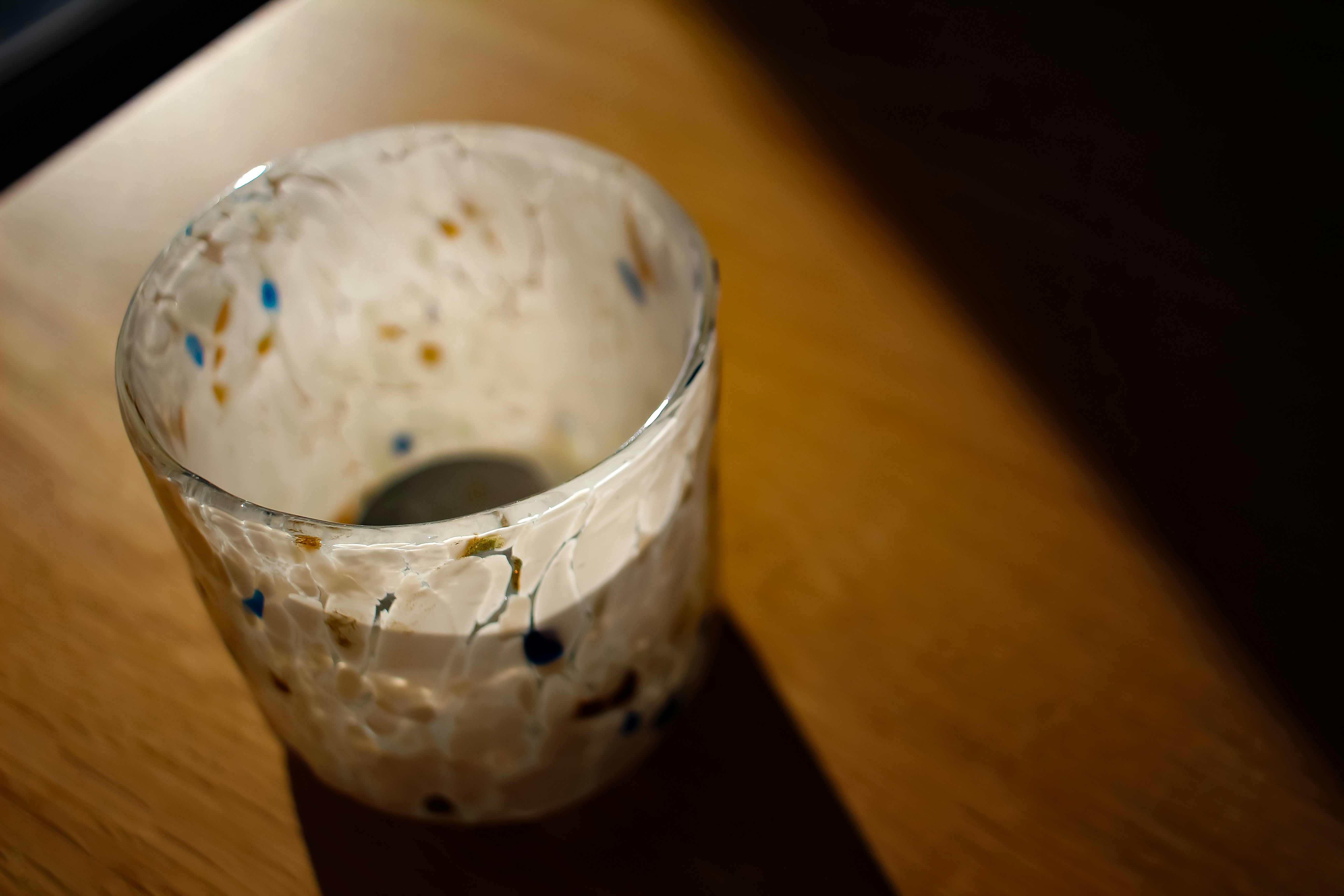 A beautifully crafted candle holder with a textured surface, illuminated by soft natural light, casting gentle shadows on a wooden table.