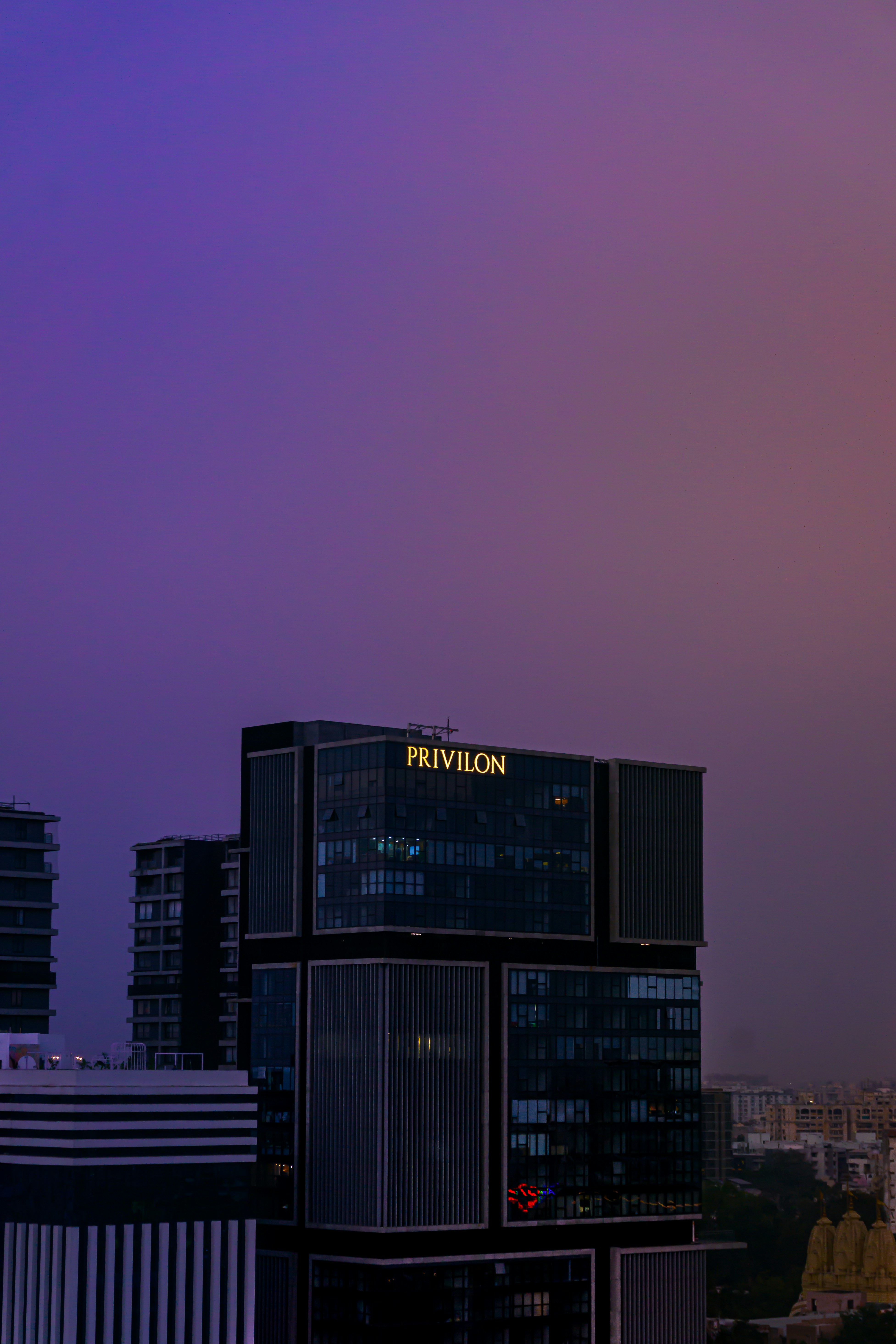 Modern high-rise building with illuminated signage against a twilight sky, showcasing urban architecture and ambiance.