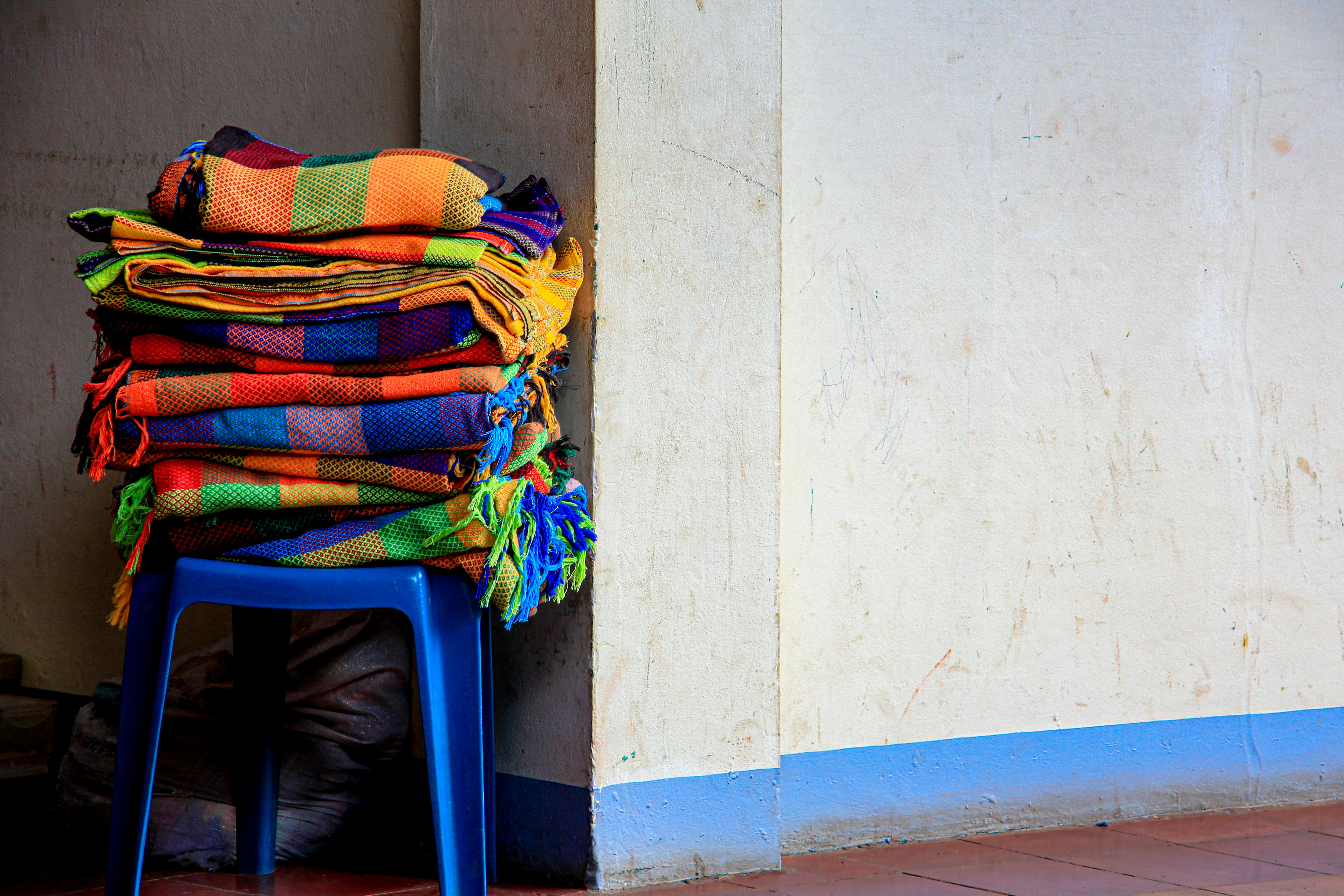blue yellow and red textile on blue plastic chair