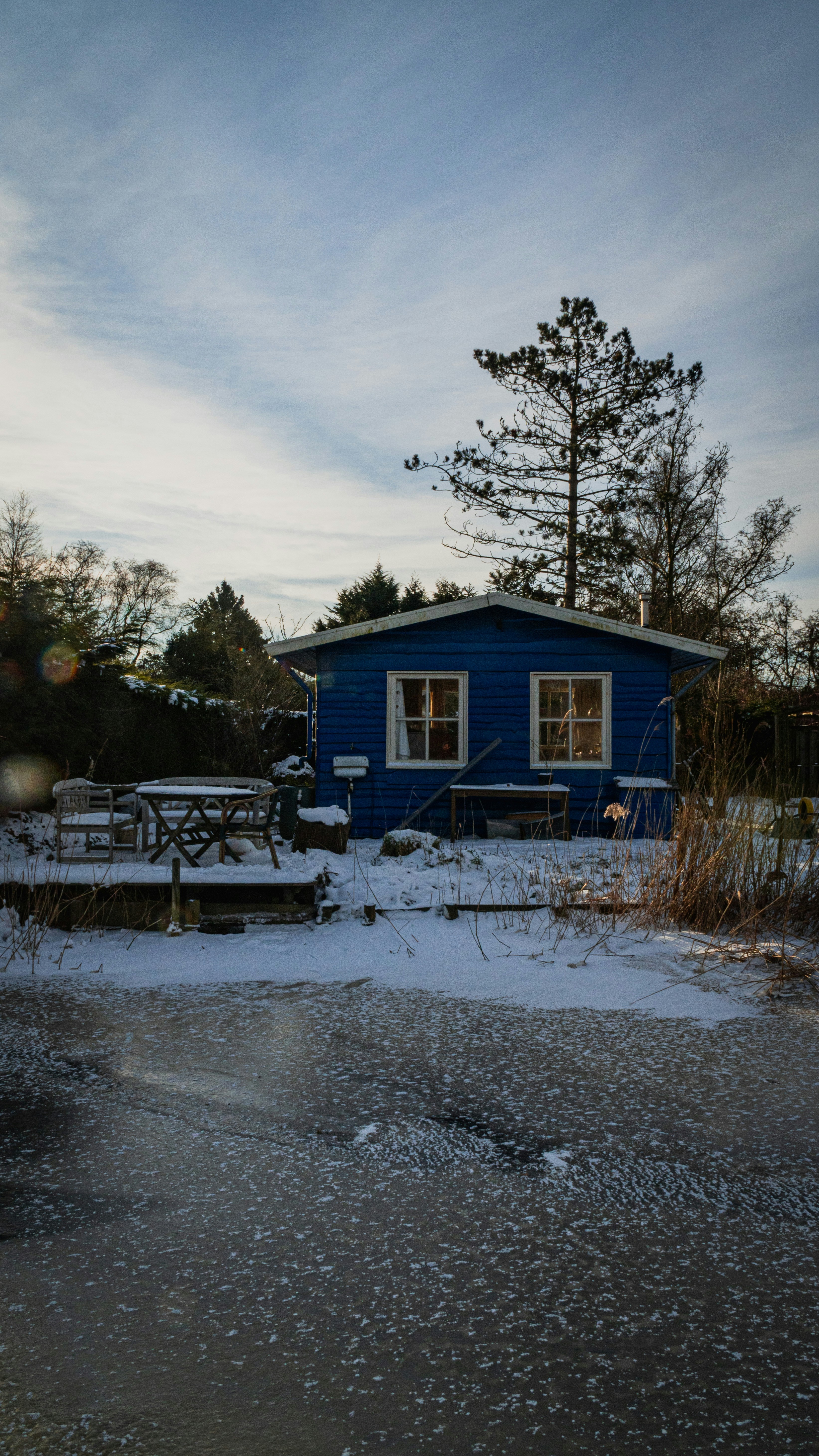Blue Cabin on a Frosted Pond Under a Quiet Winter Sky